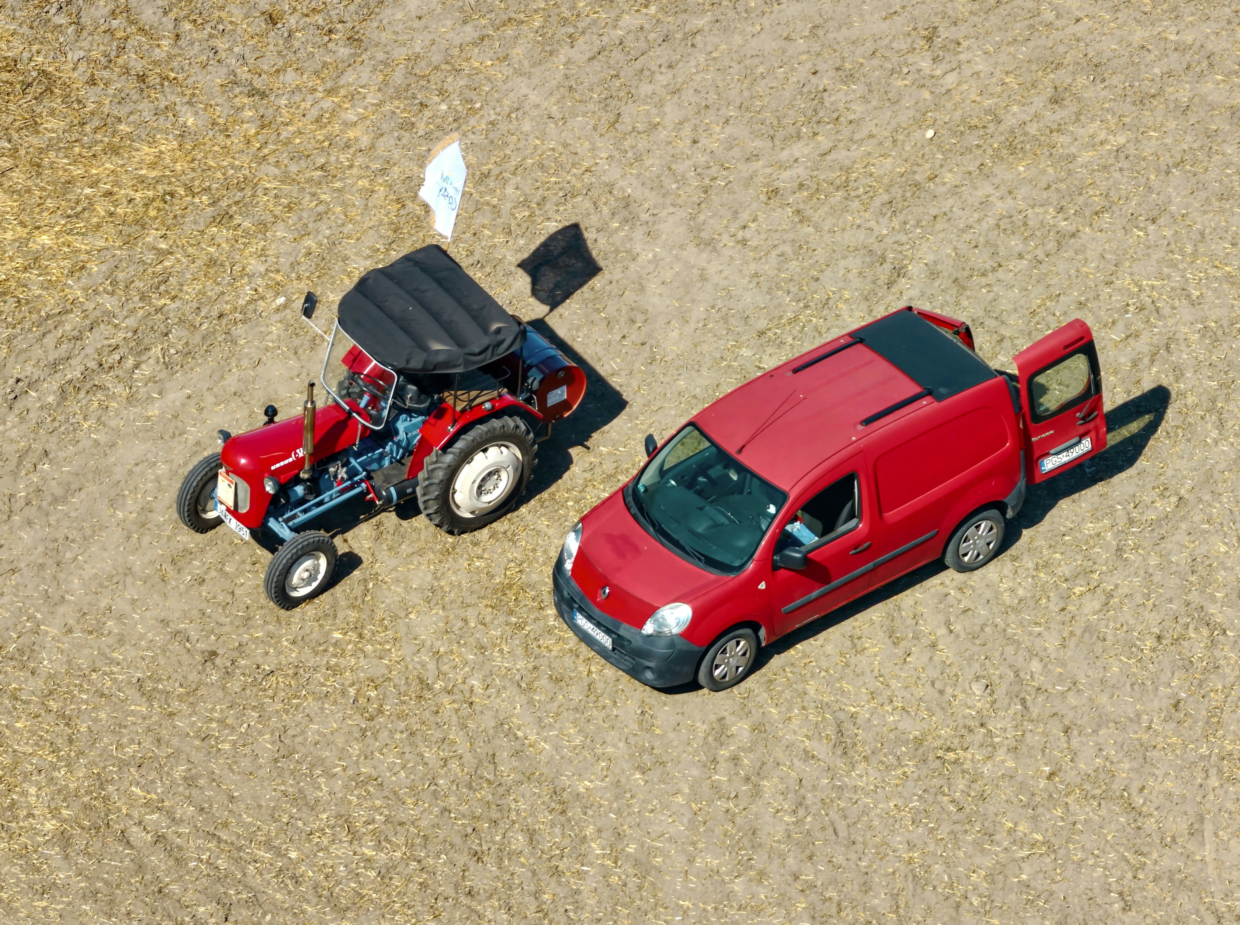 Red Pickup and Tractor: Aerial Close-Up on Sand
