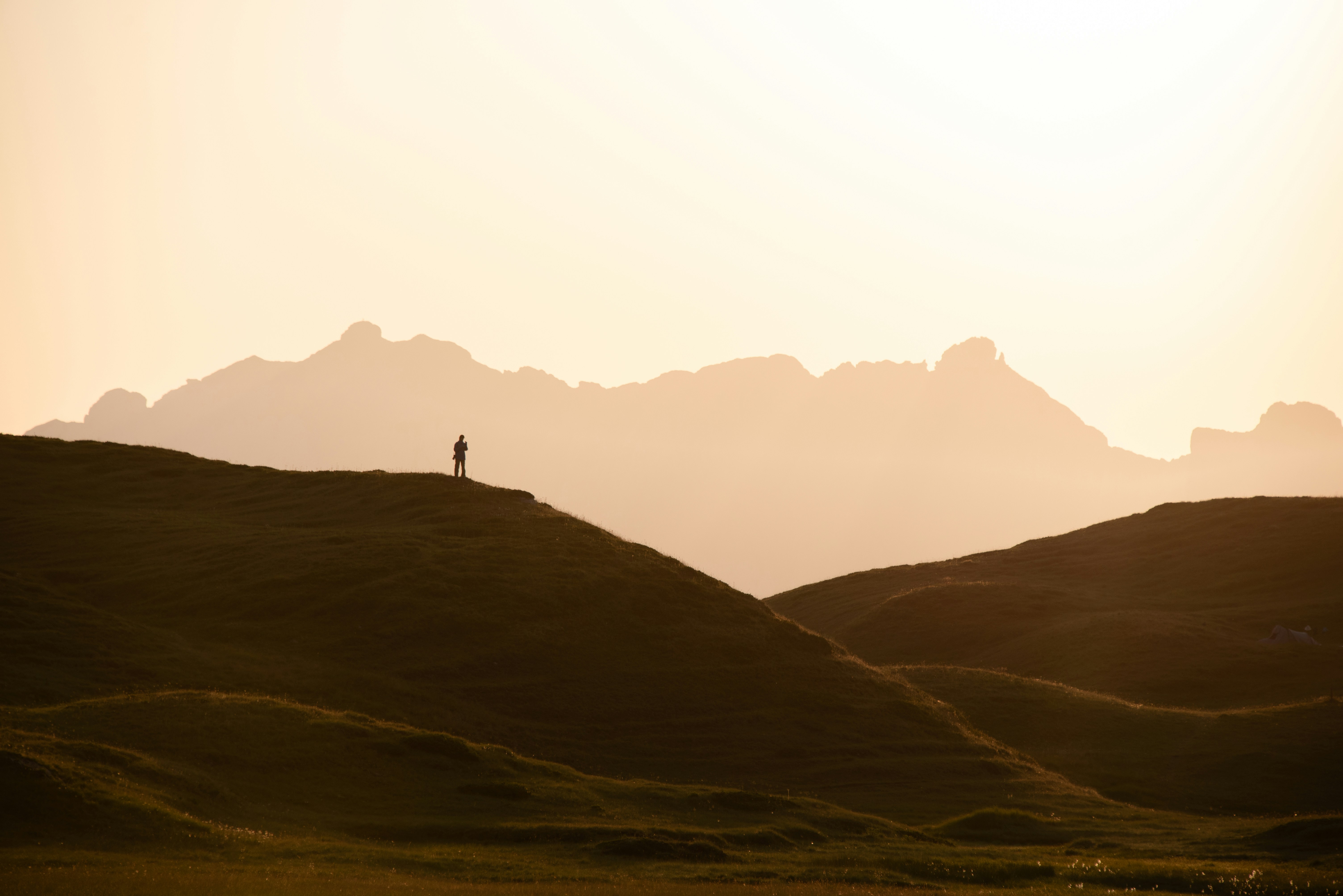  lone silhouette above rolling dunes at golden hour
