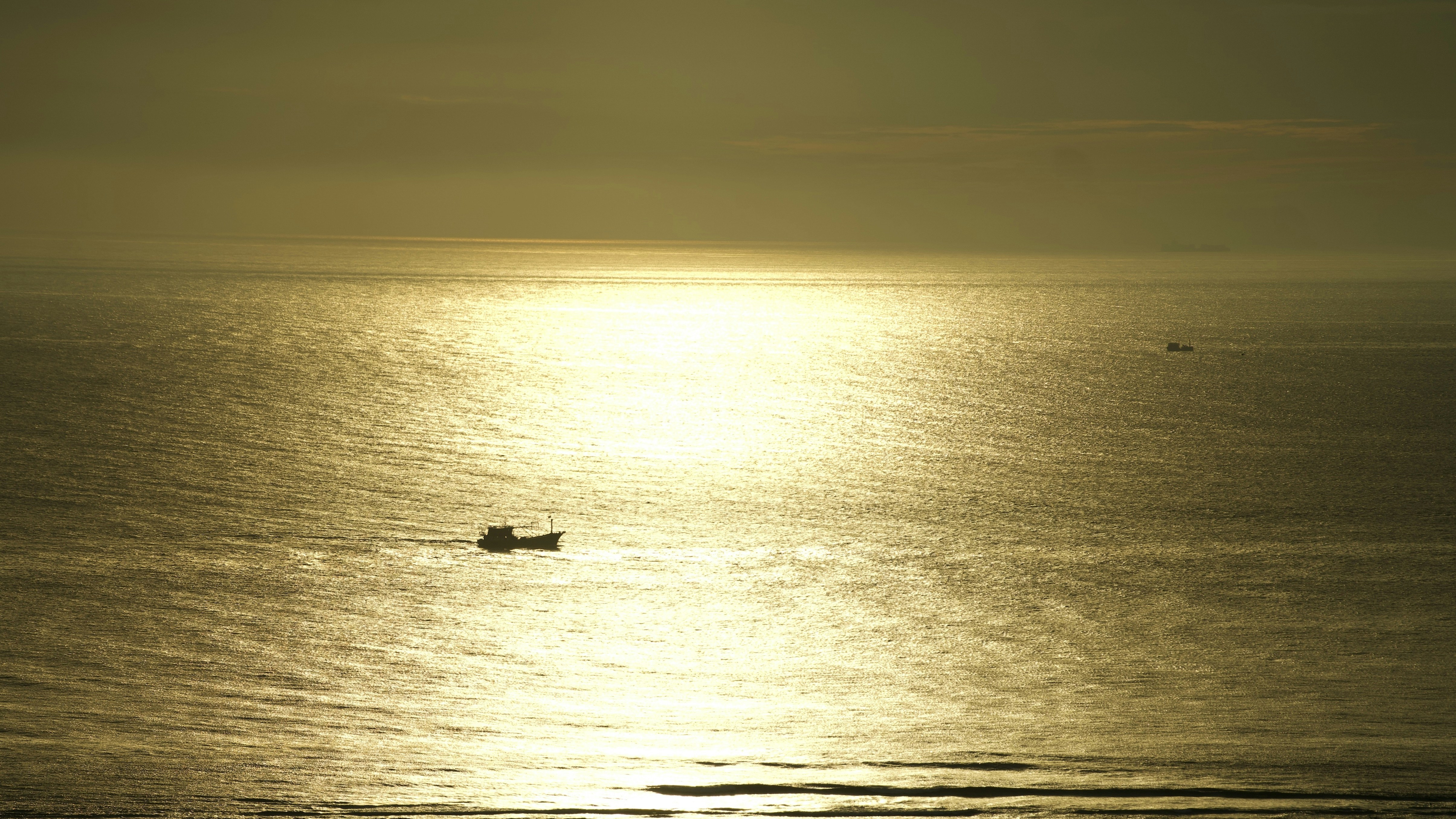 Golden Horizon: A Quiet Boat on a Glimmering Sea at Sunset