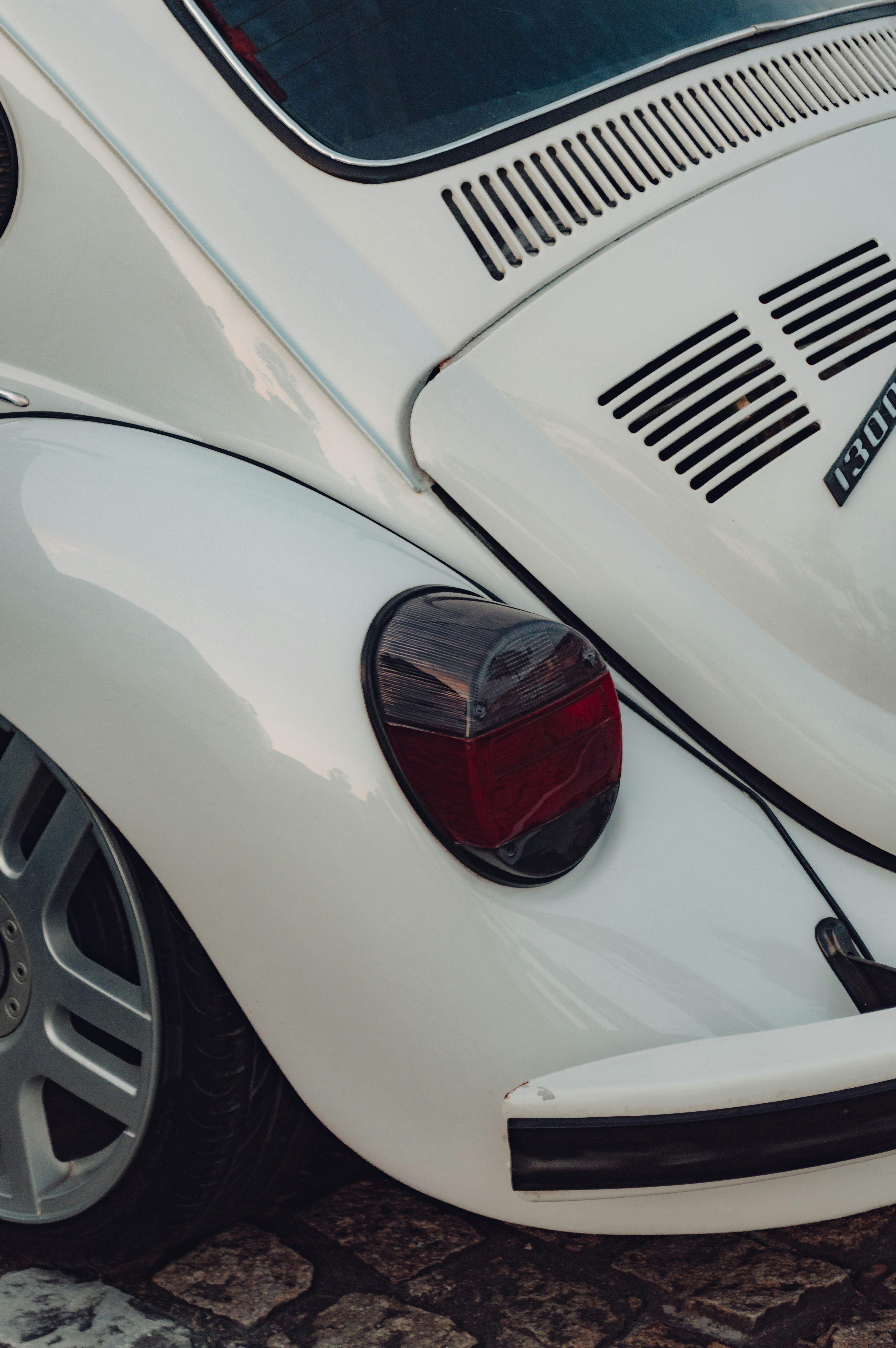 Rear quarter view of a white Volkswagen Beetle with a custom silver wheel