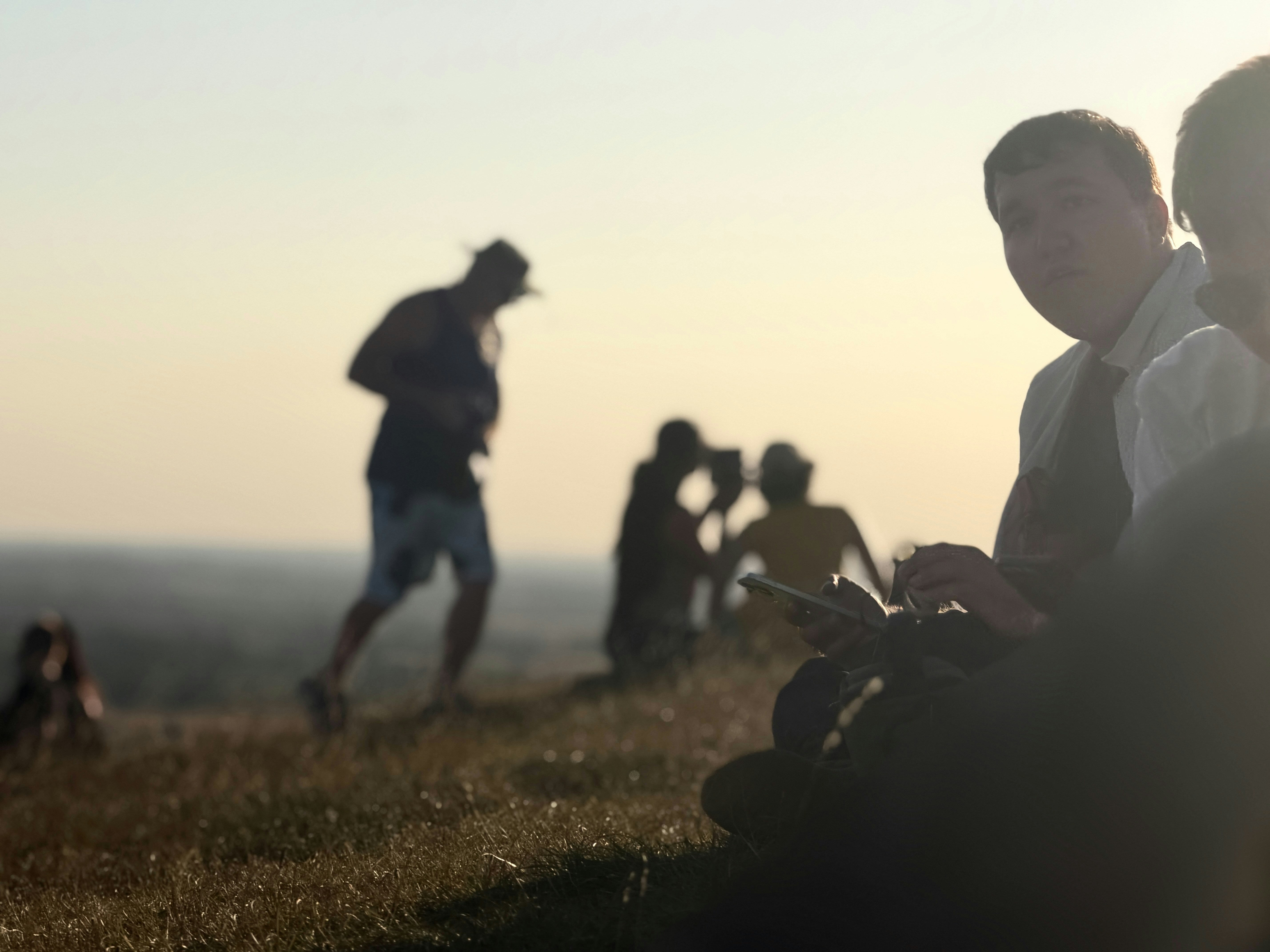 Distant silhouettes at dusk: friends on a hillside