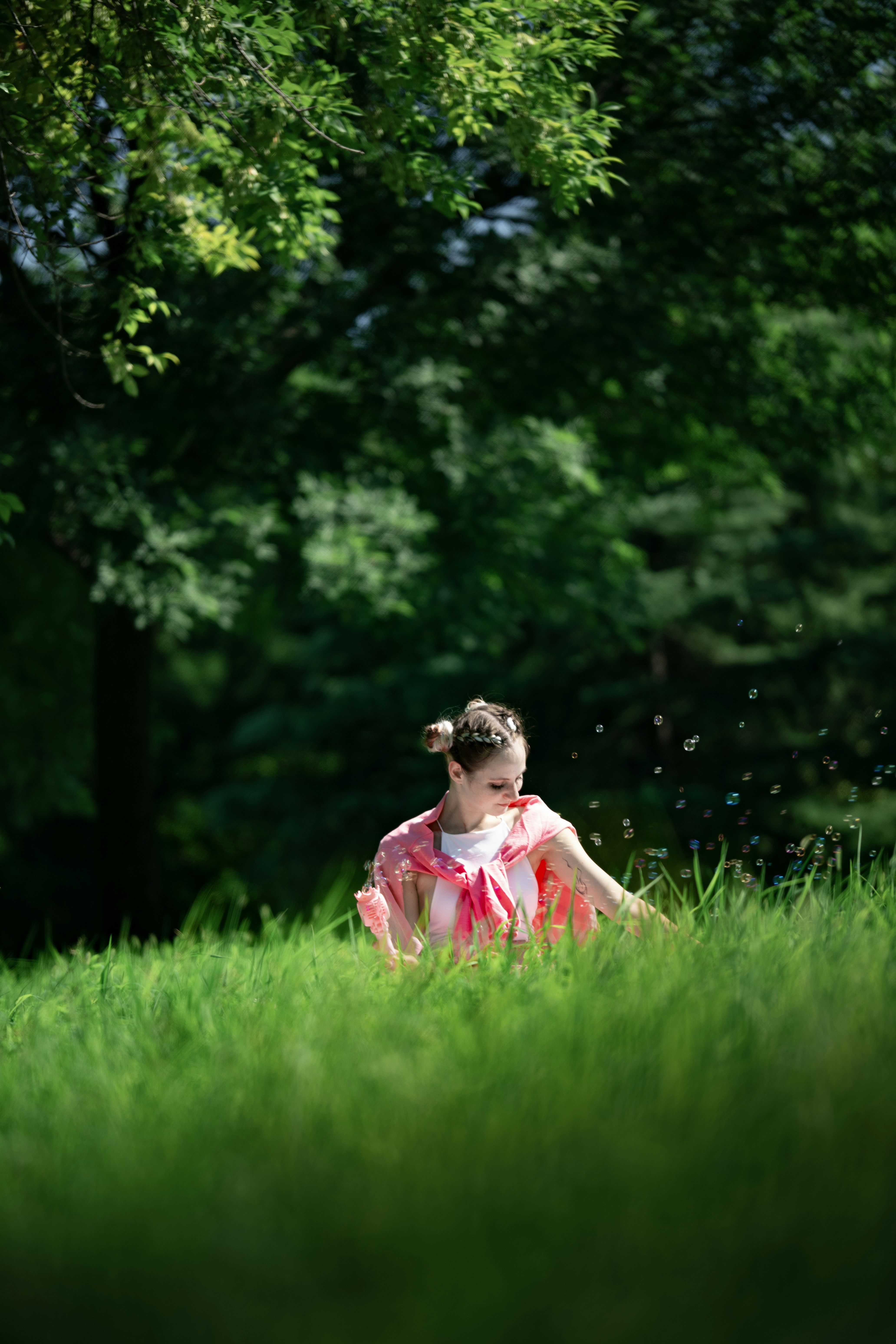 Girl in pink blouse at the edge of sunlit meadow