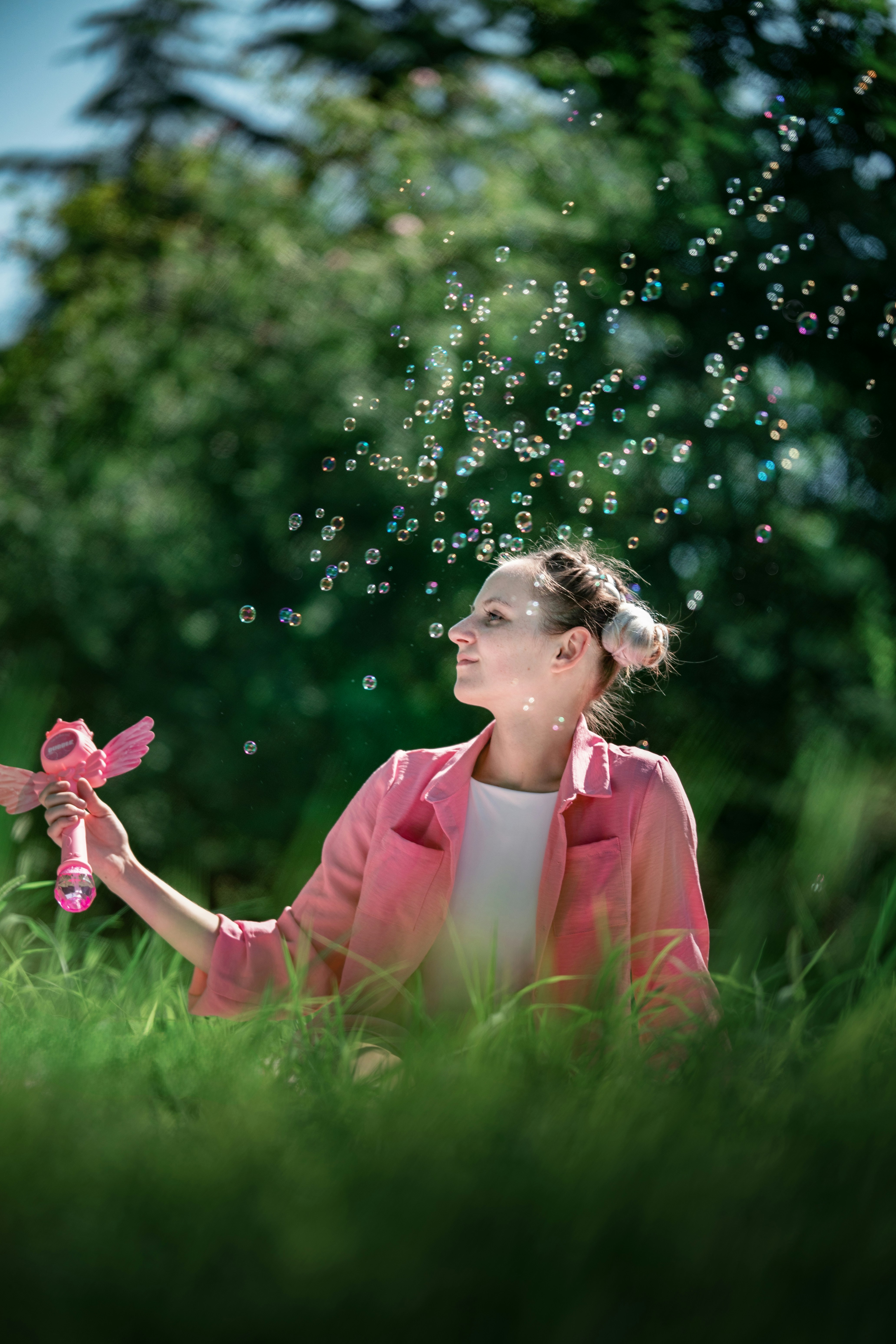  bubbles on a sunny day: a girl with a pink jacket mid-play