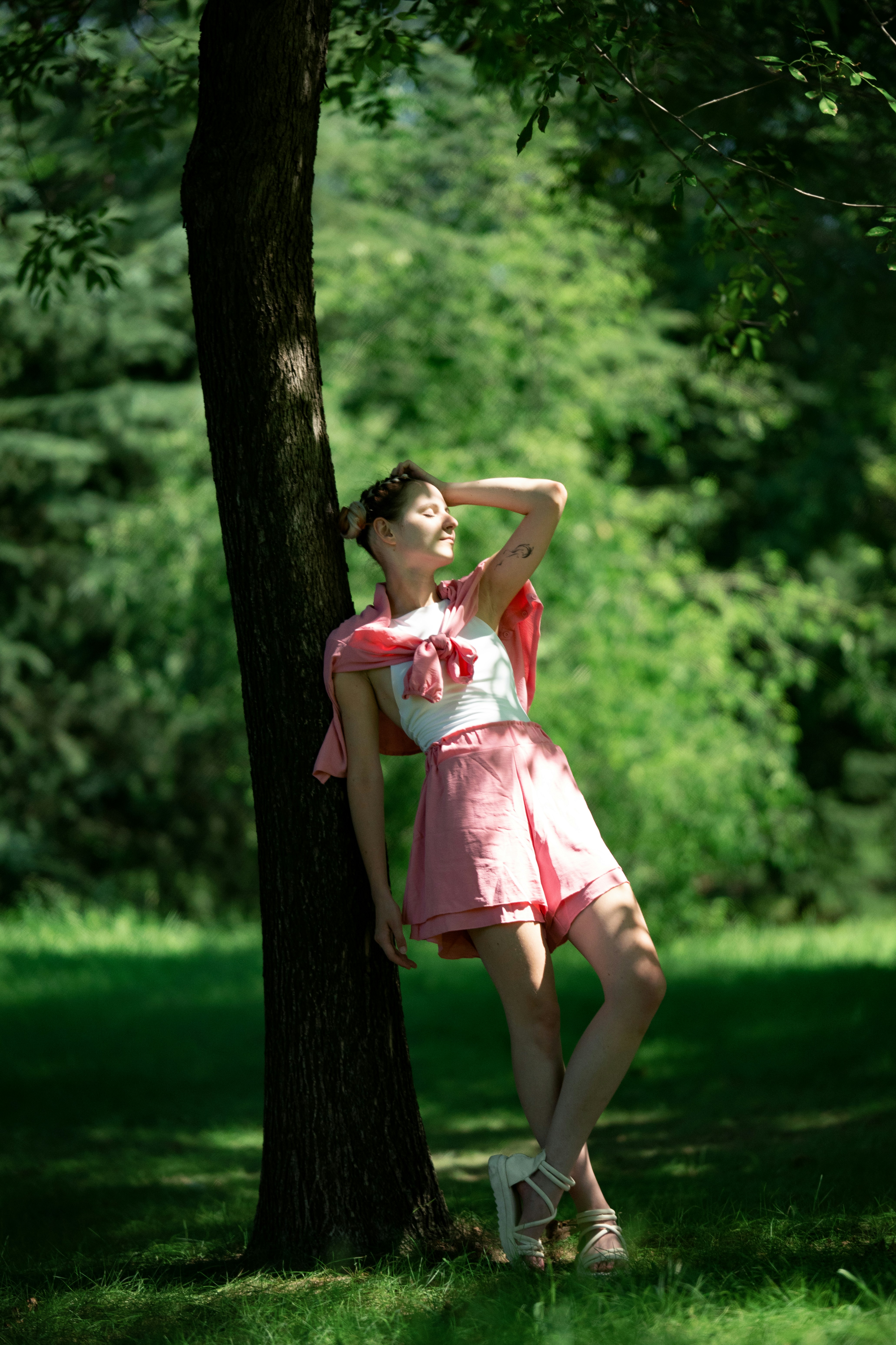 Youthful poise under a tree: pink set and sunlit calm