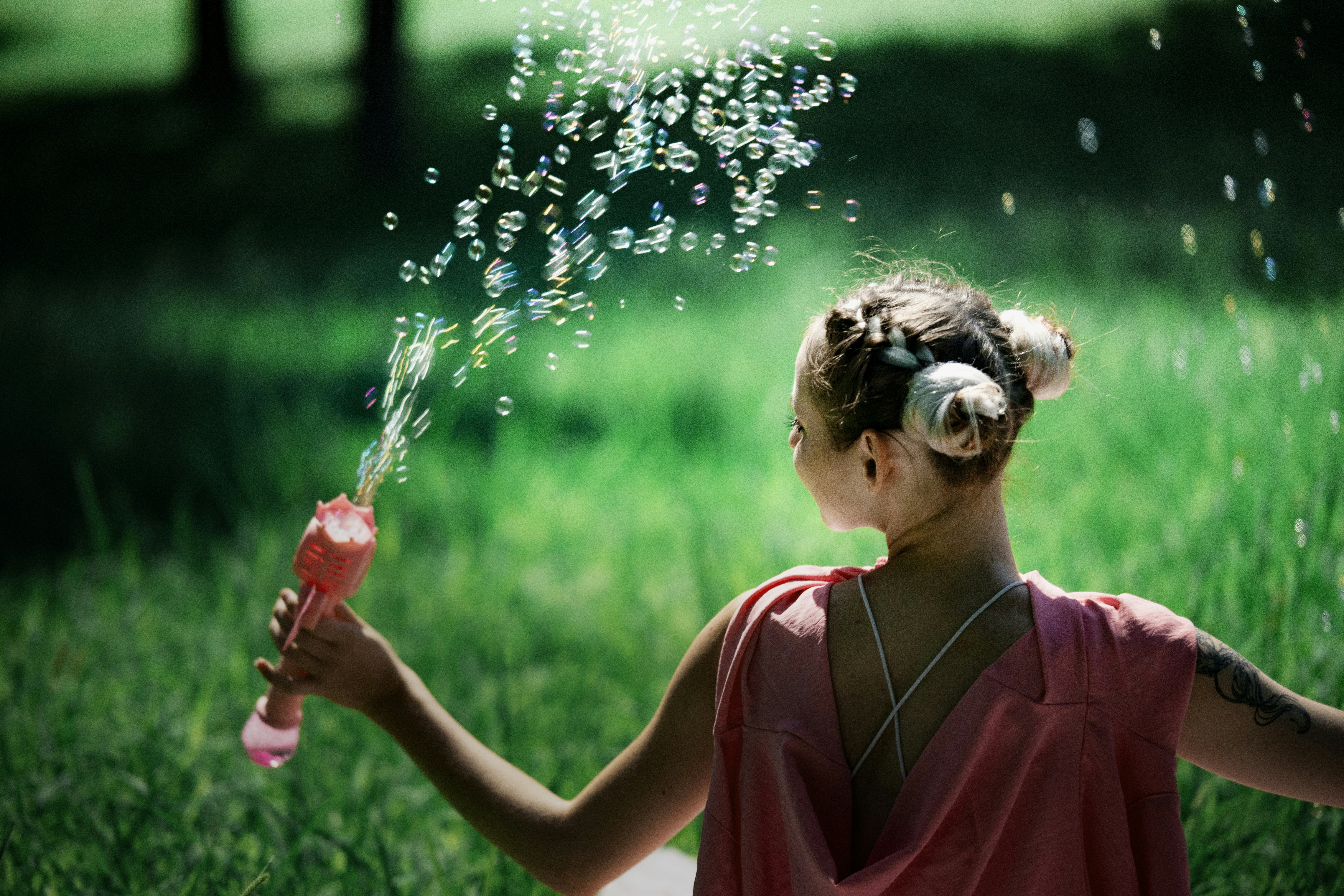 Splashing joy: a girl in pink plays with a bubble blower