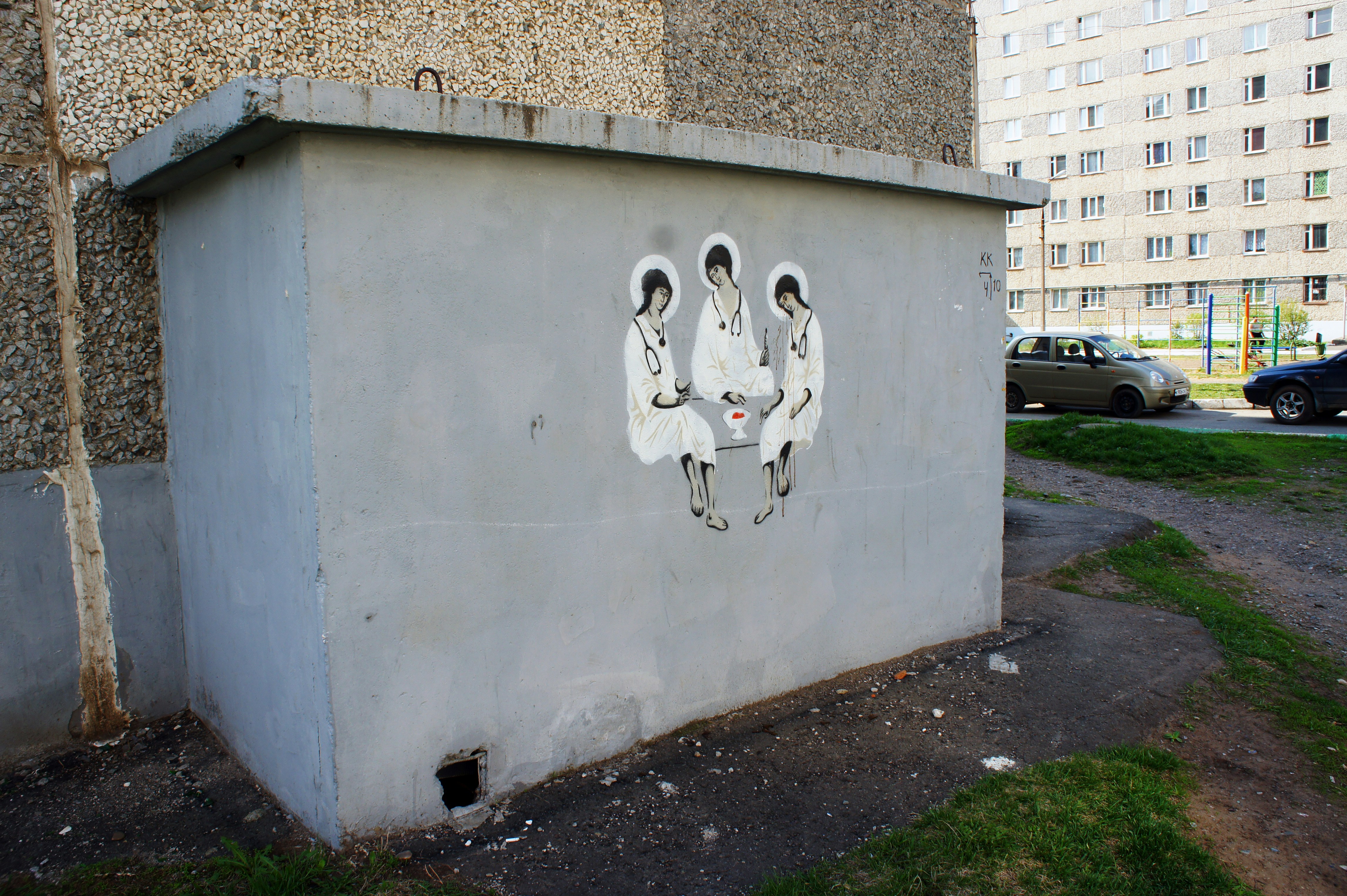 Three Figures on a Graffitied Utility Box in a Deserted Courtyard