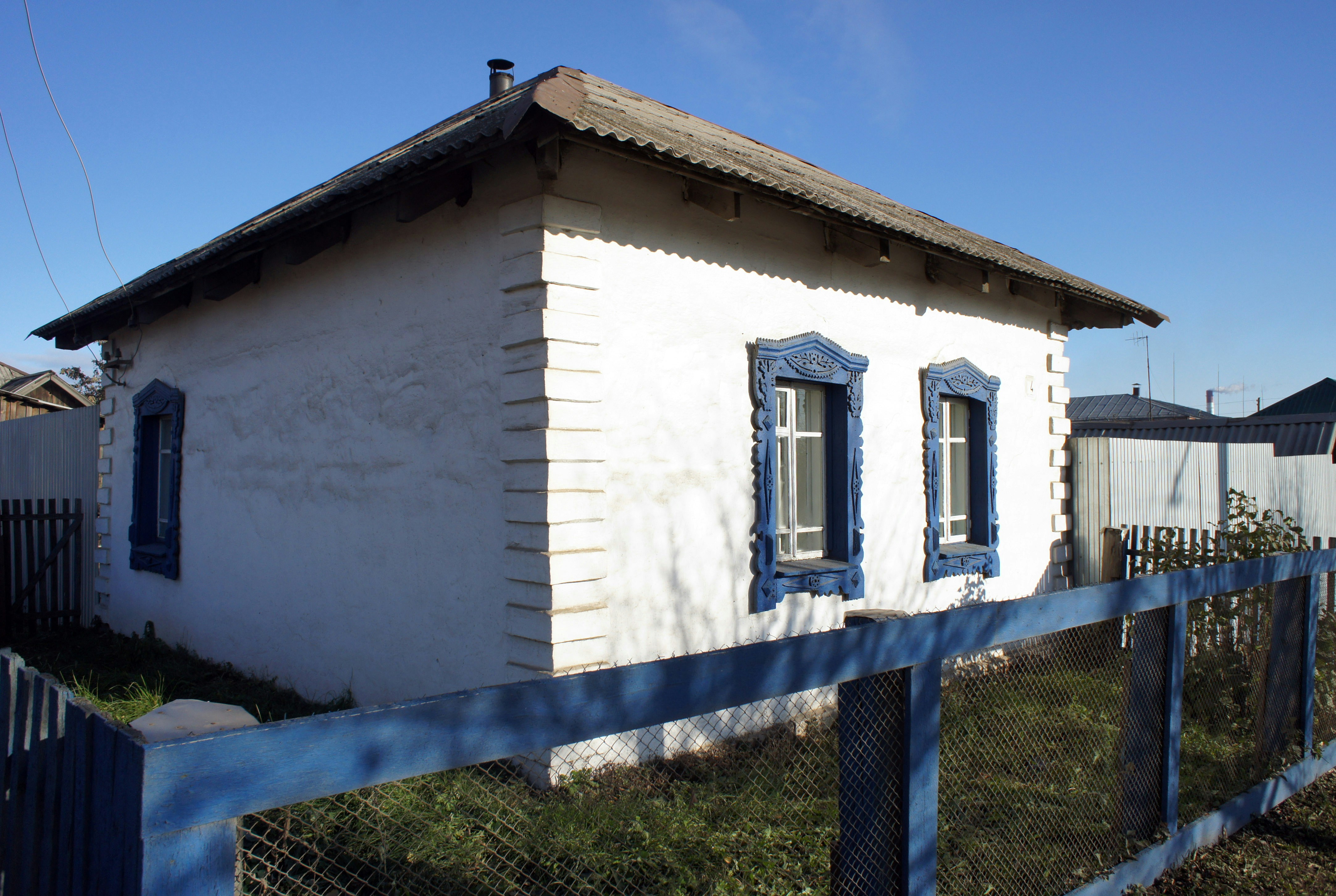 White Cottage with Blue Trims Beneath a Clear Sky