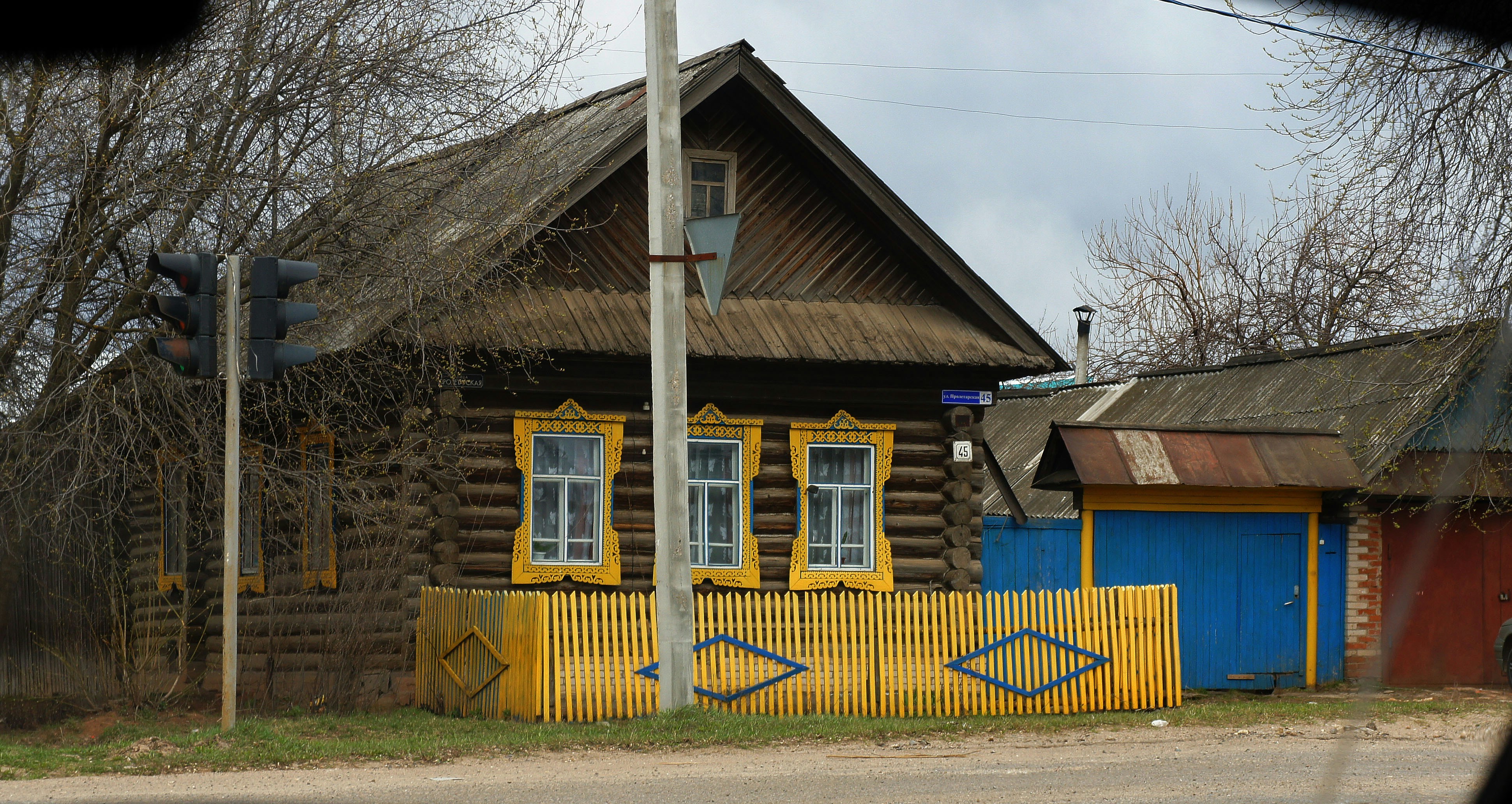 Yellow Fence and Cozy Wooden House at a Rural Street Corner