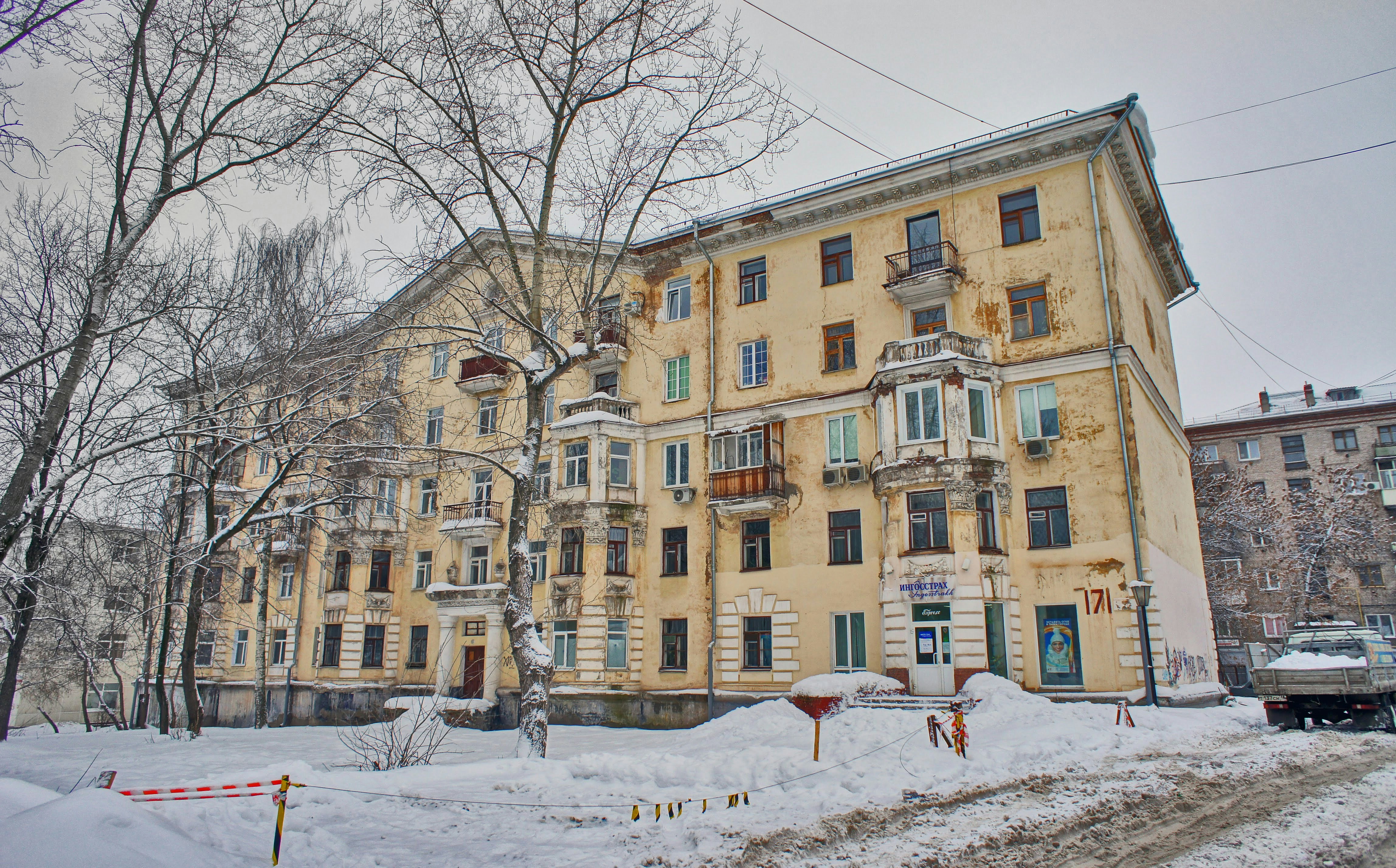 Winter Facade: A Worn Yellow Building Quietly Standing Against Snow