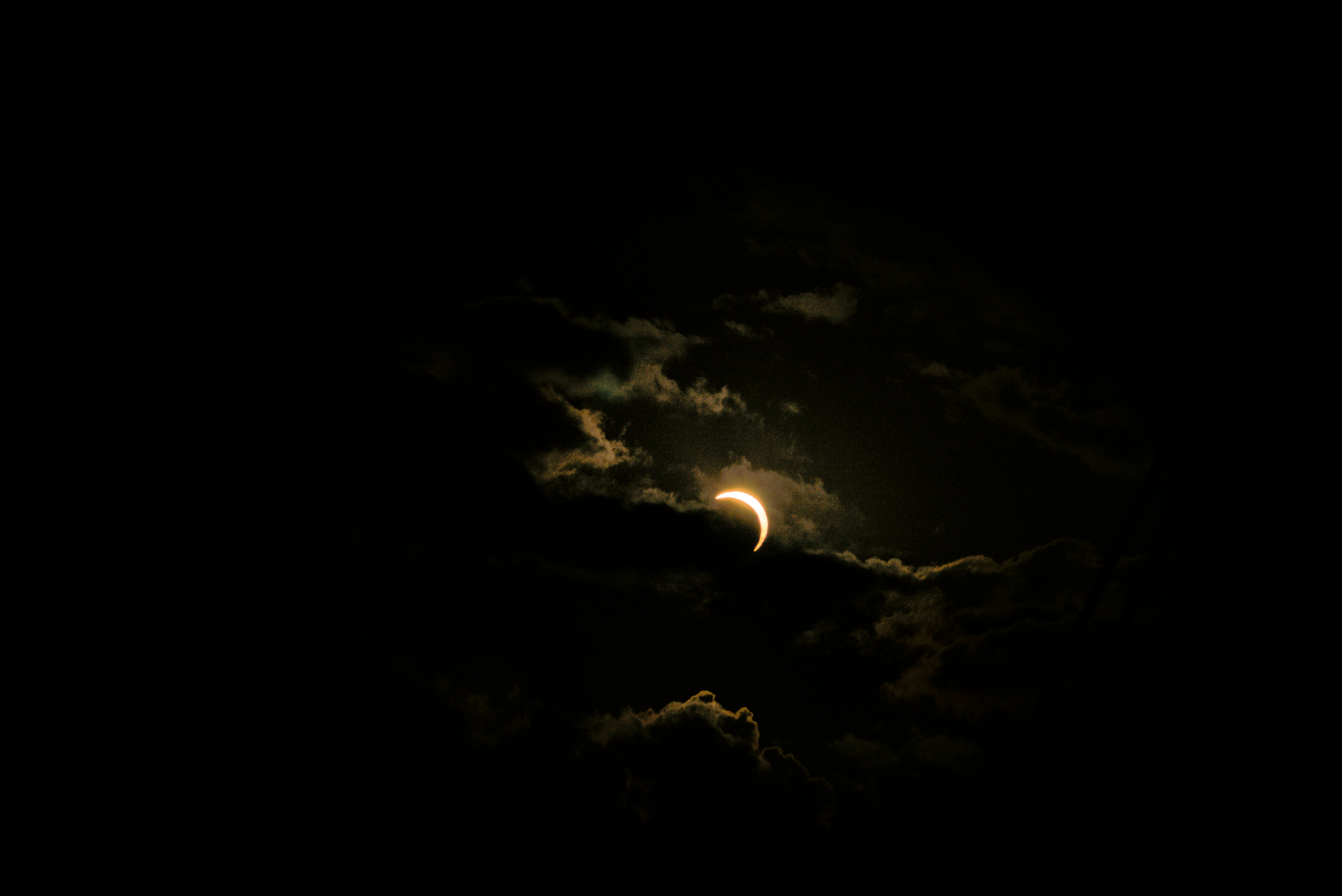 Partial Solar Eclipse: Crescent Moon Piercing through Night Clouds