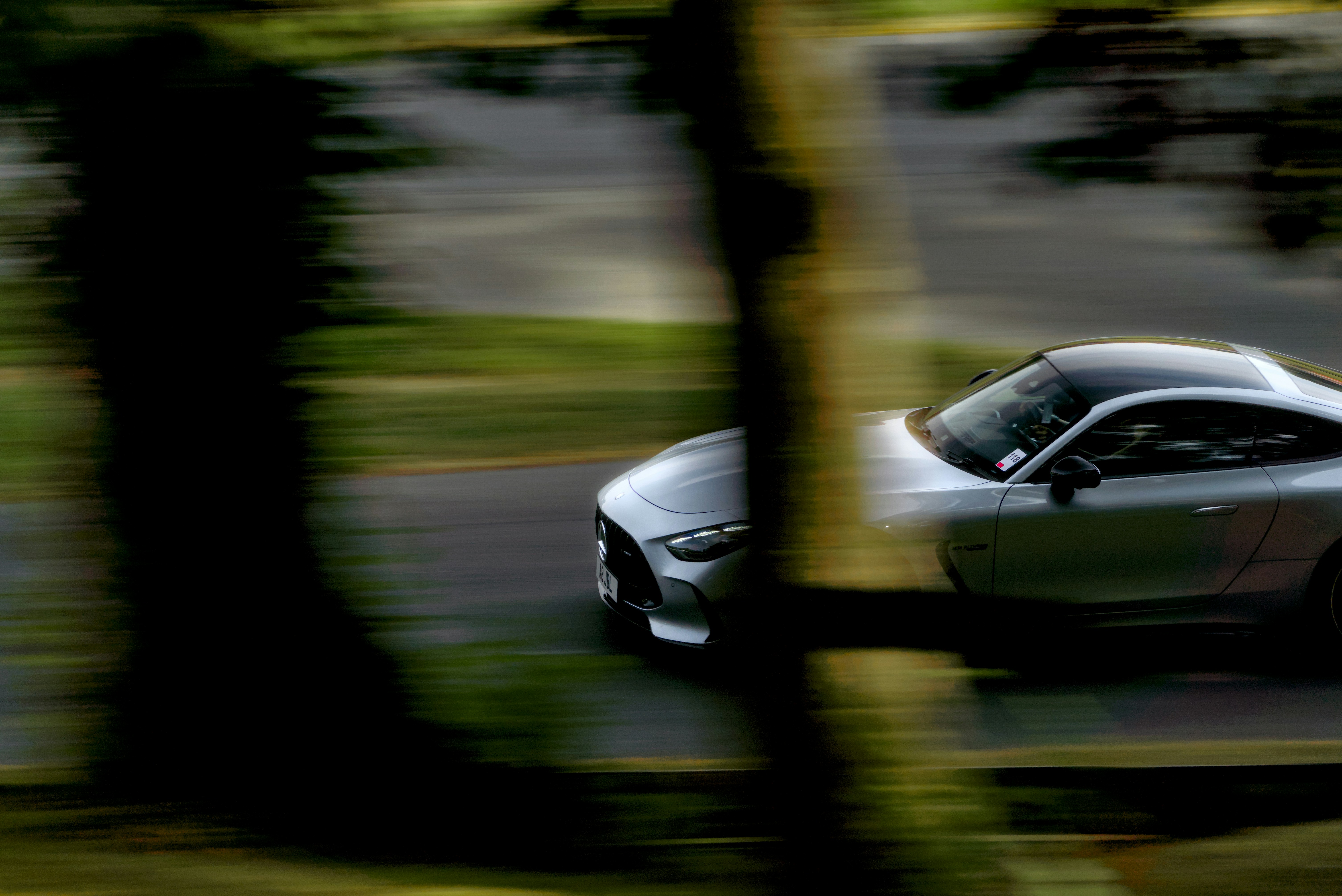 Silver Coupe in Motion Through Shaded Street Corridor