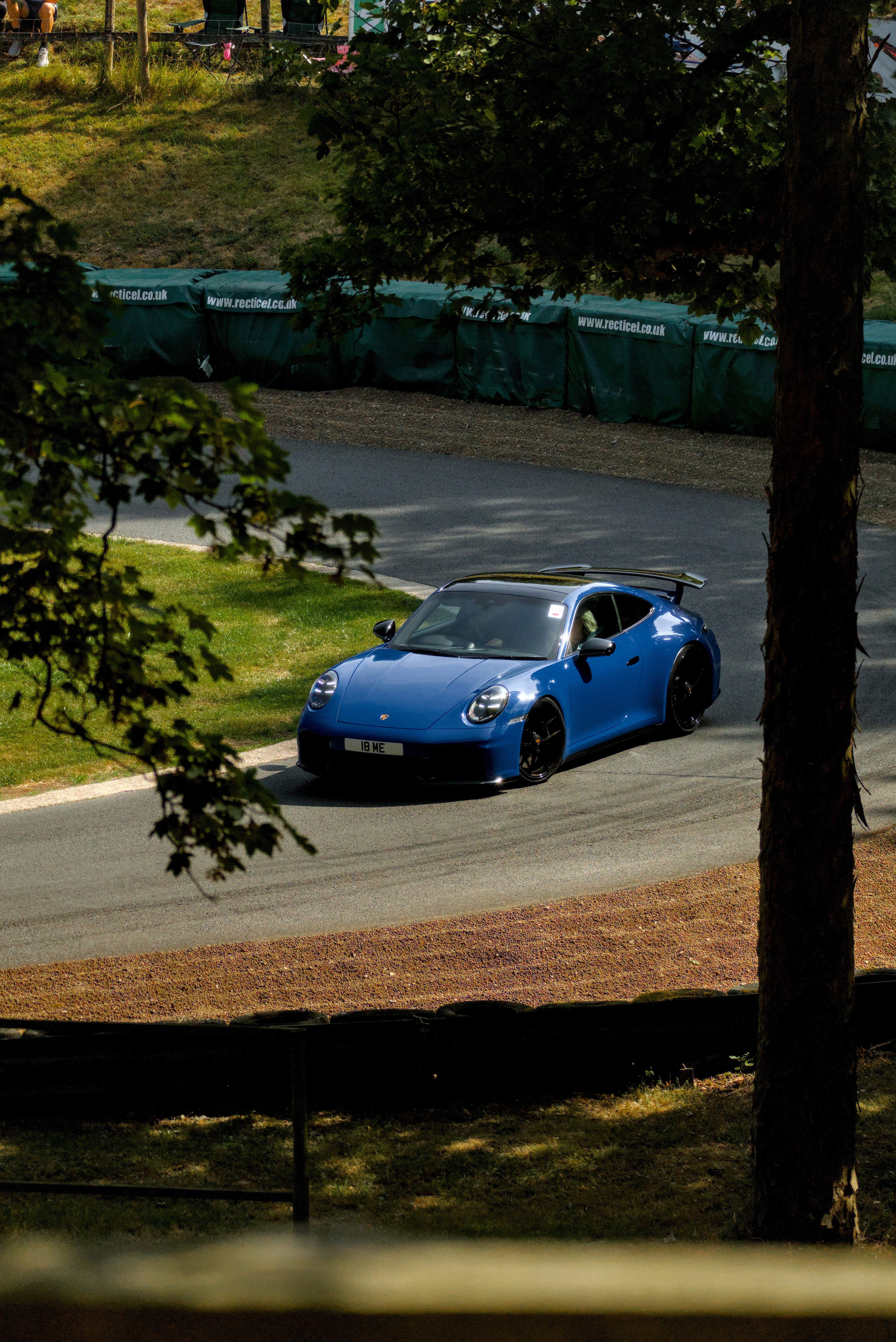 Blue Porsche Rounds the Corner under Dappled Shade