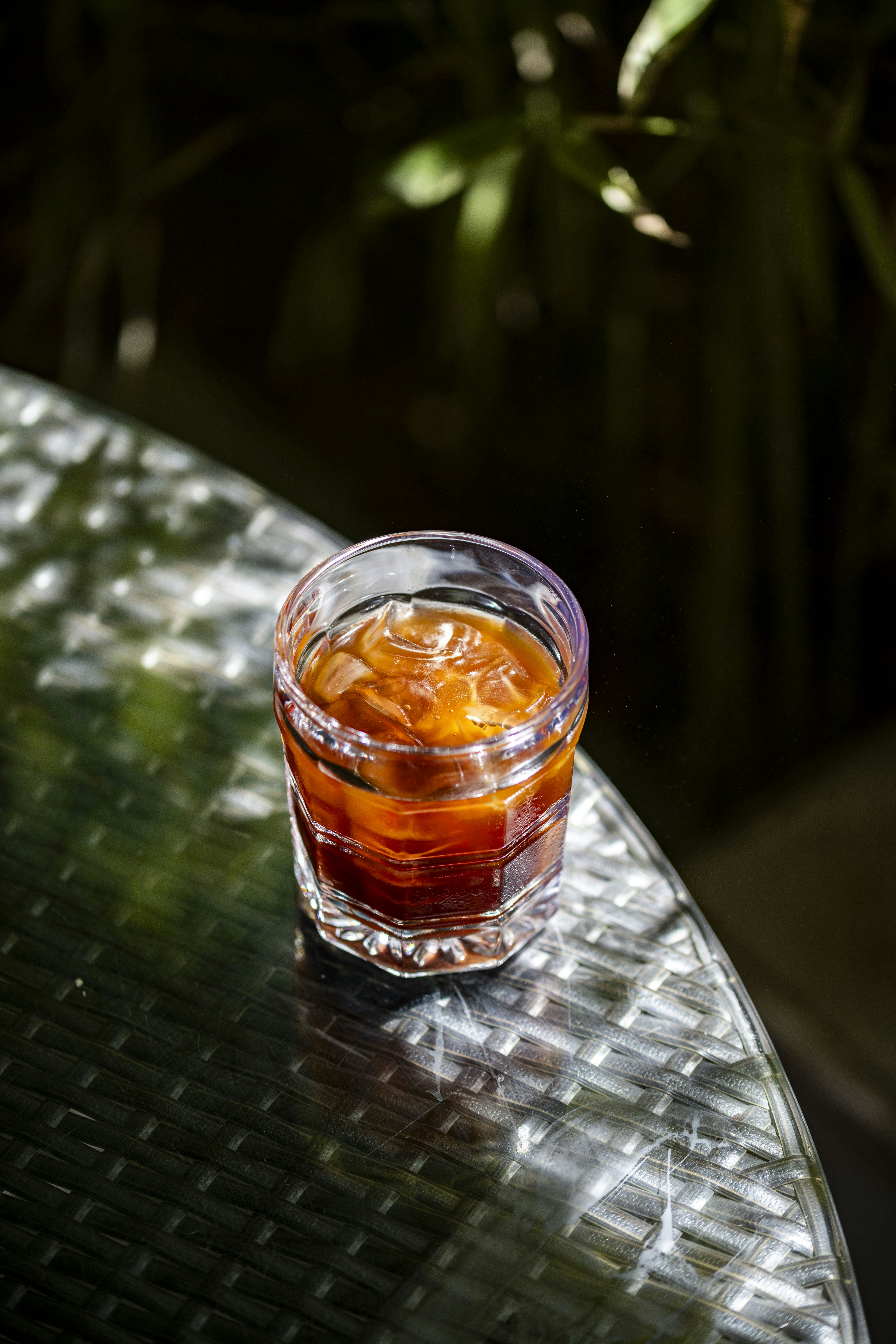 Glass of Amber on a Sunlit Rattan Table