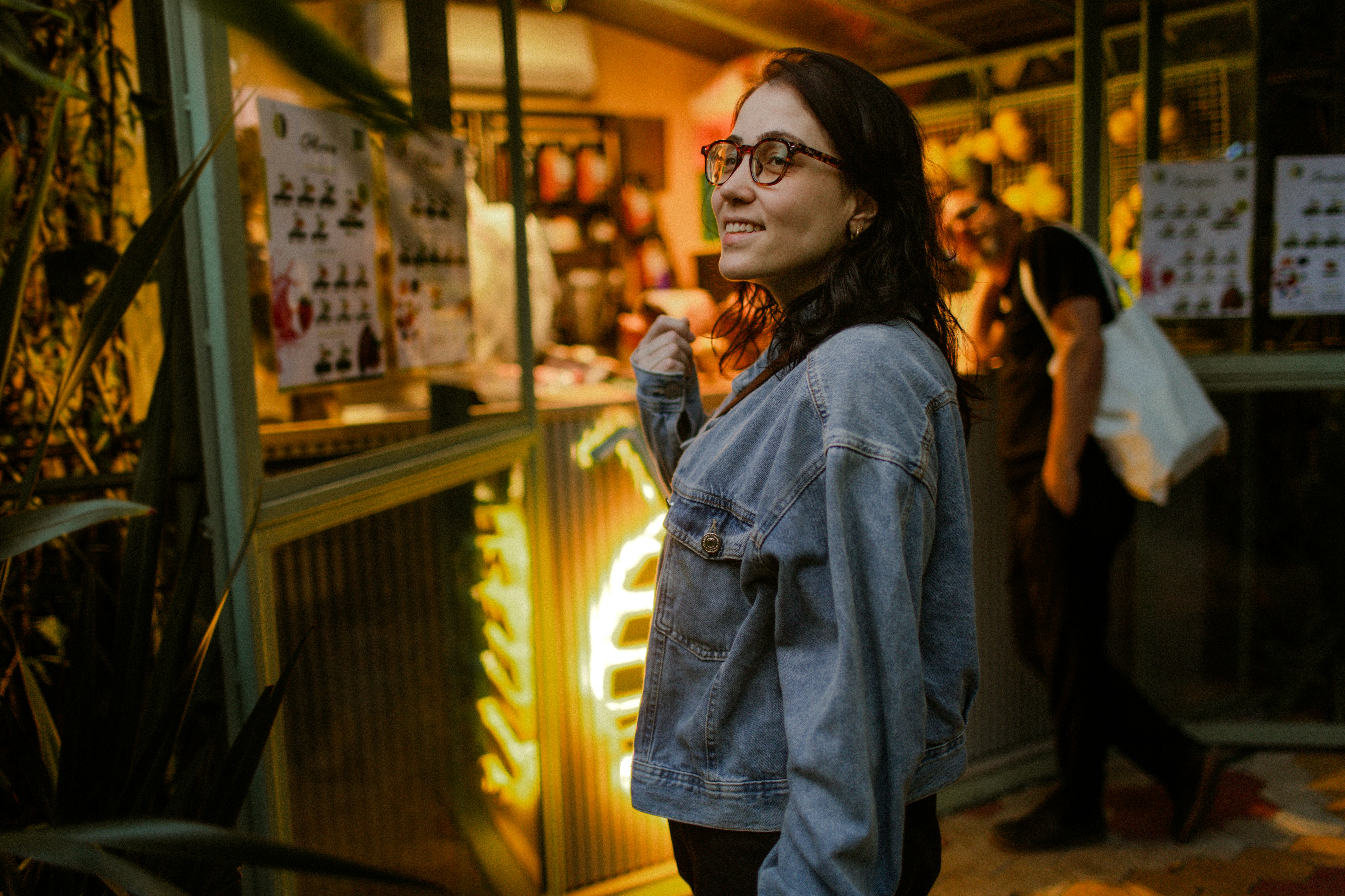 Warm Neon Glint: Woman in Denim at a Market Stall