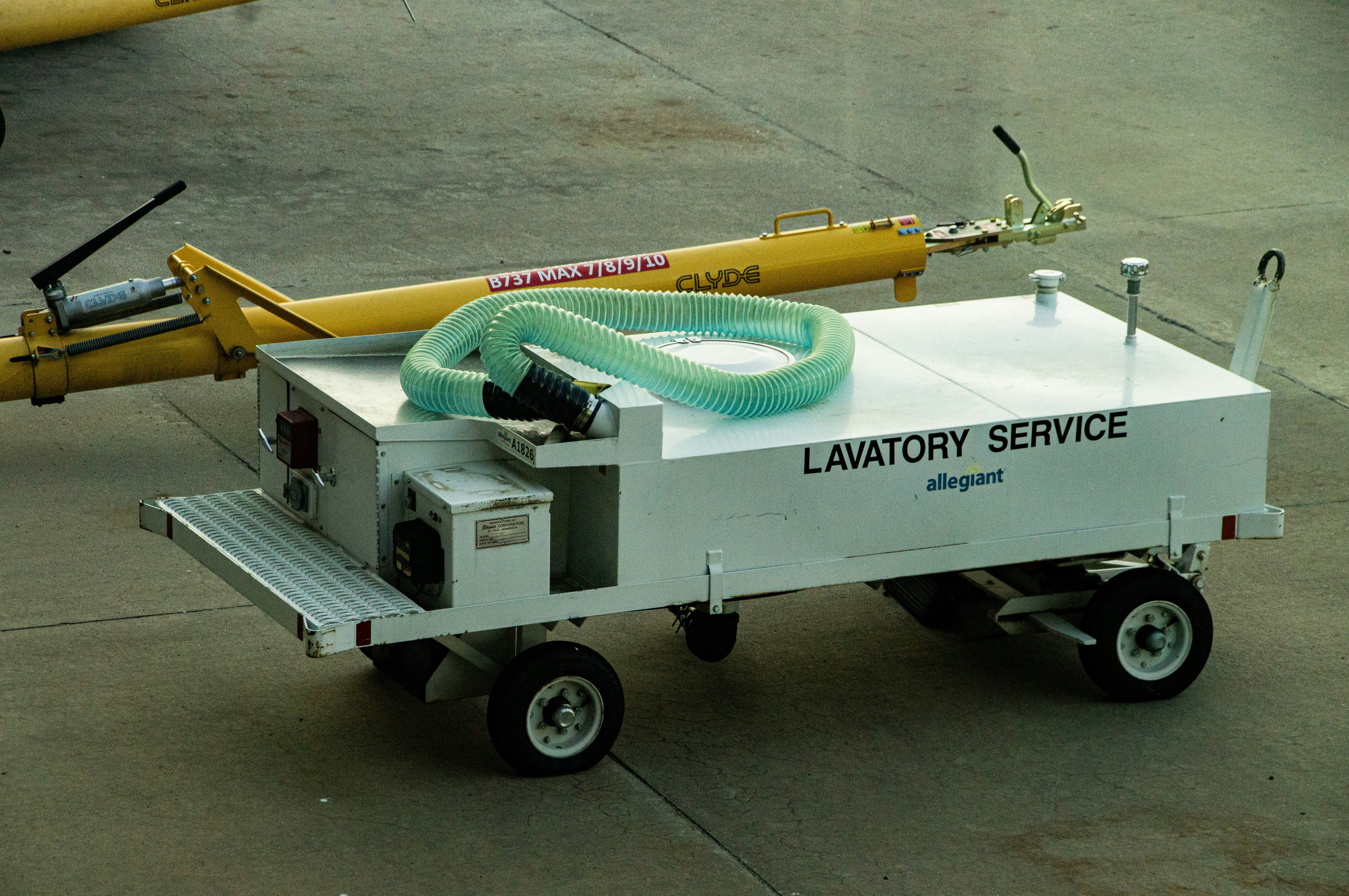 Ground Support Lavatory Cart with Bright Green Hose Aligned by Quayside