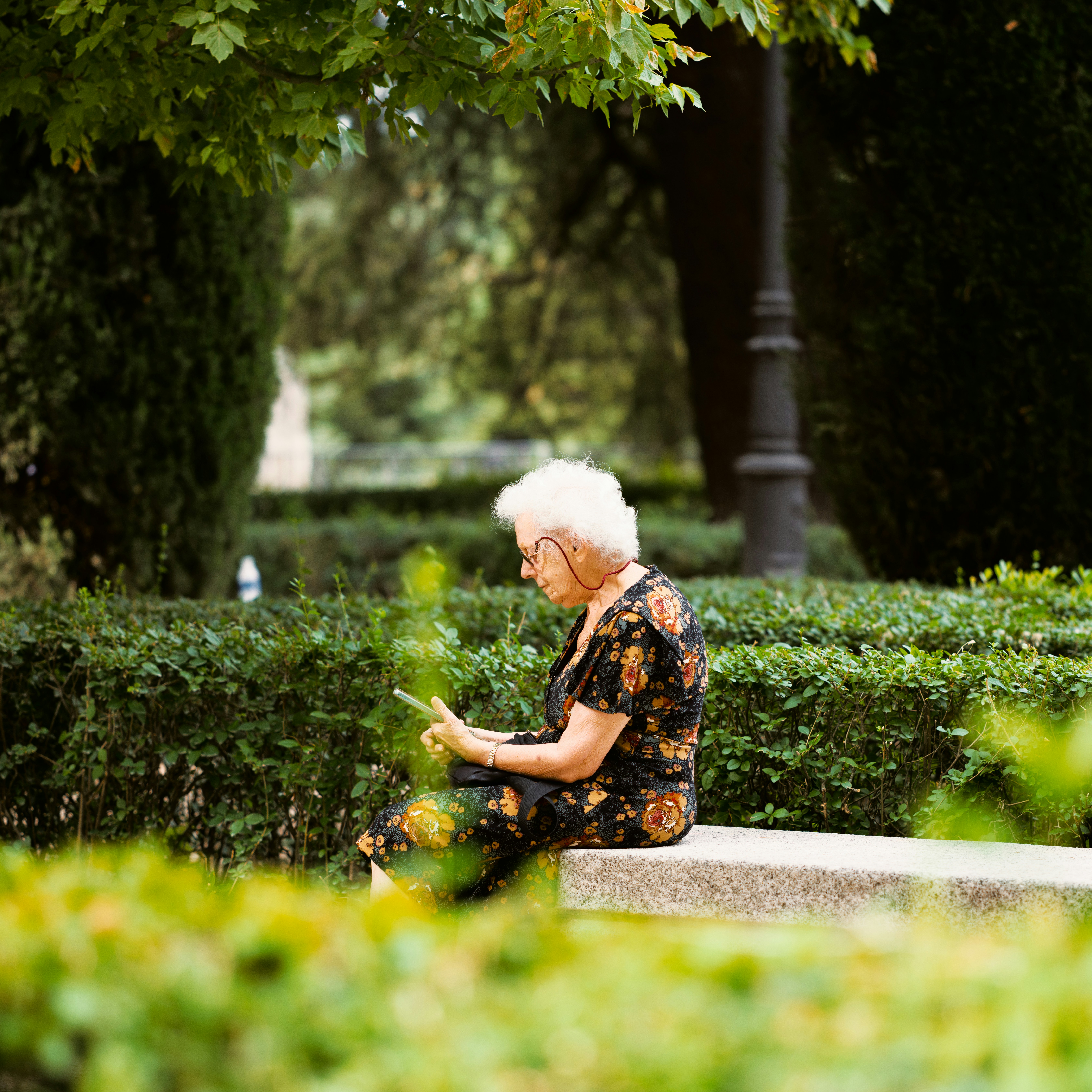 Quiet Moment on the Park Bench: Elderly Woman in Floral Dress
