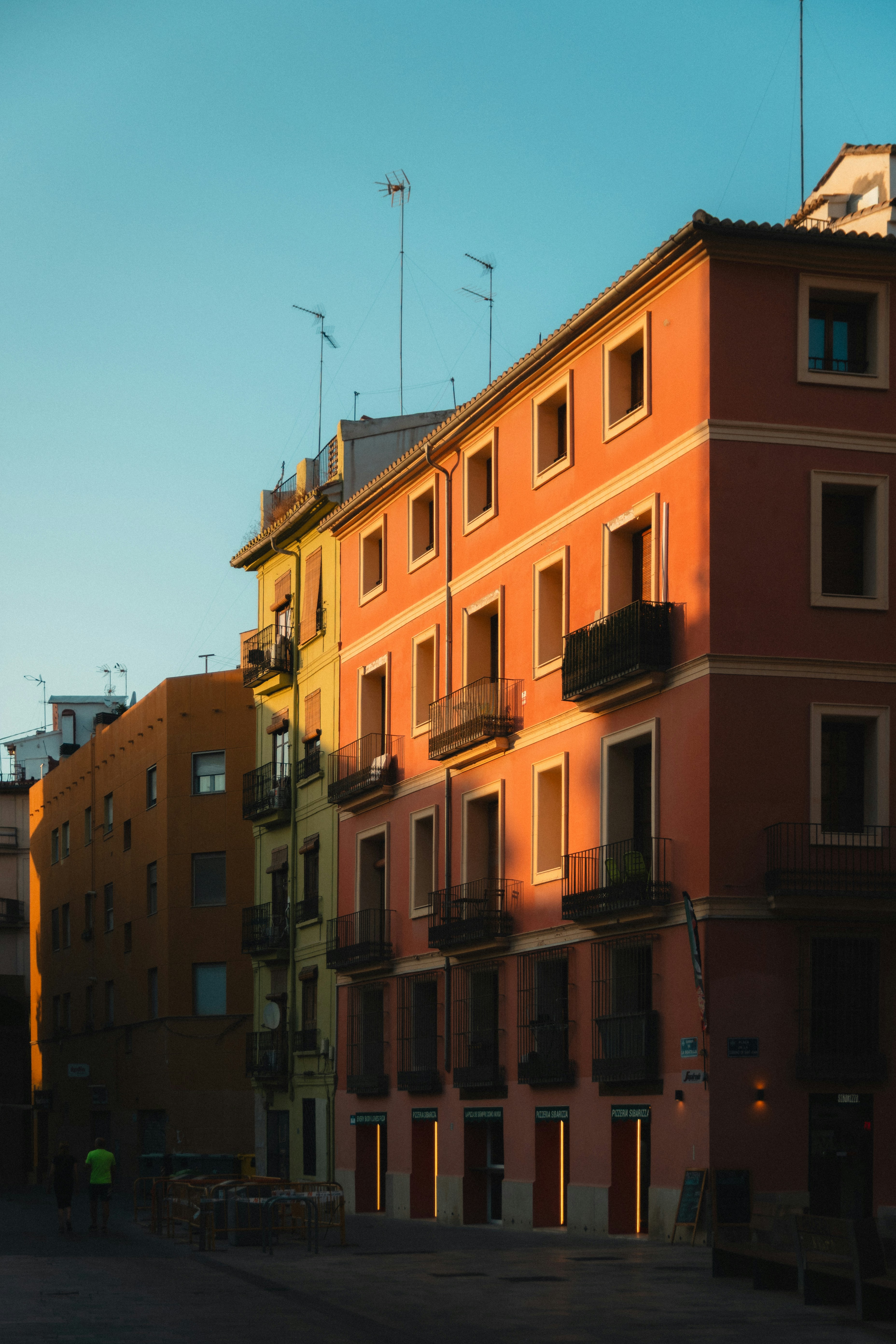 Colourful apartment buildings catch the warm evening sunlight on a quiet street in Valencia, Spain.