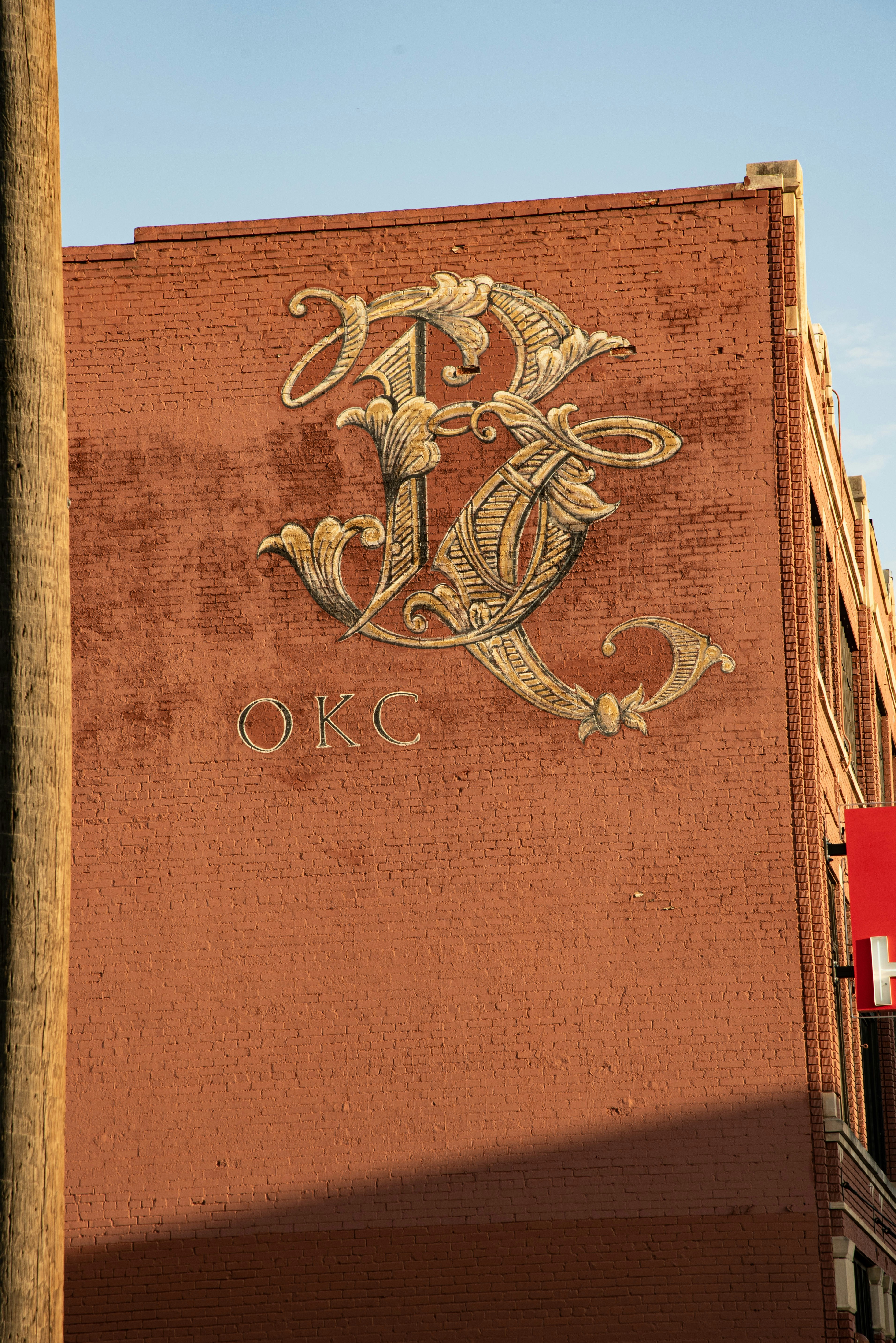 Brickwork Crest: OKC monogram on sunlit mural
