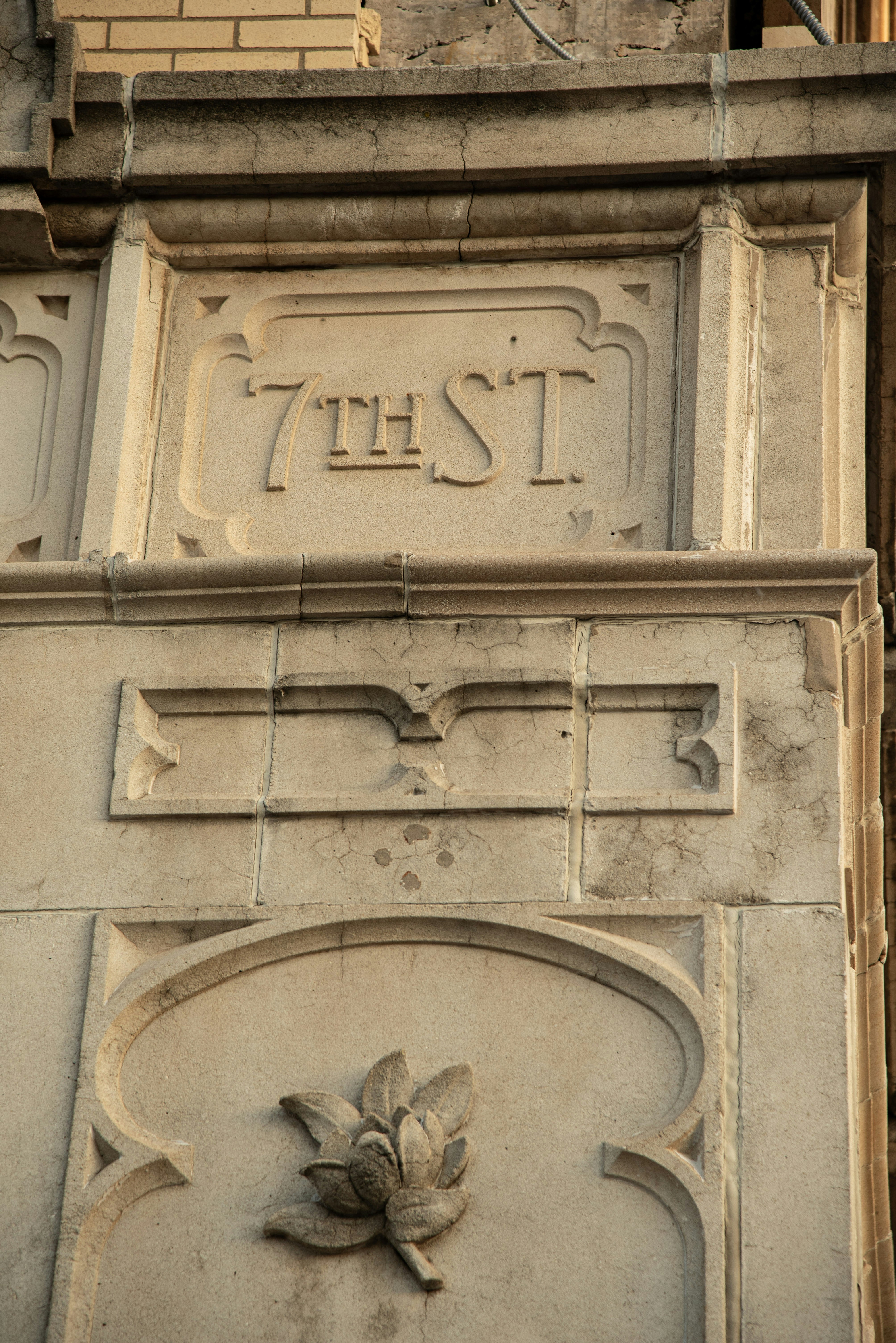 Stonework Centerpiece: Carved Floral Emblem Beneath Th Street Sign