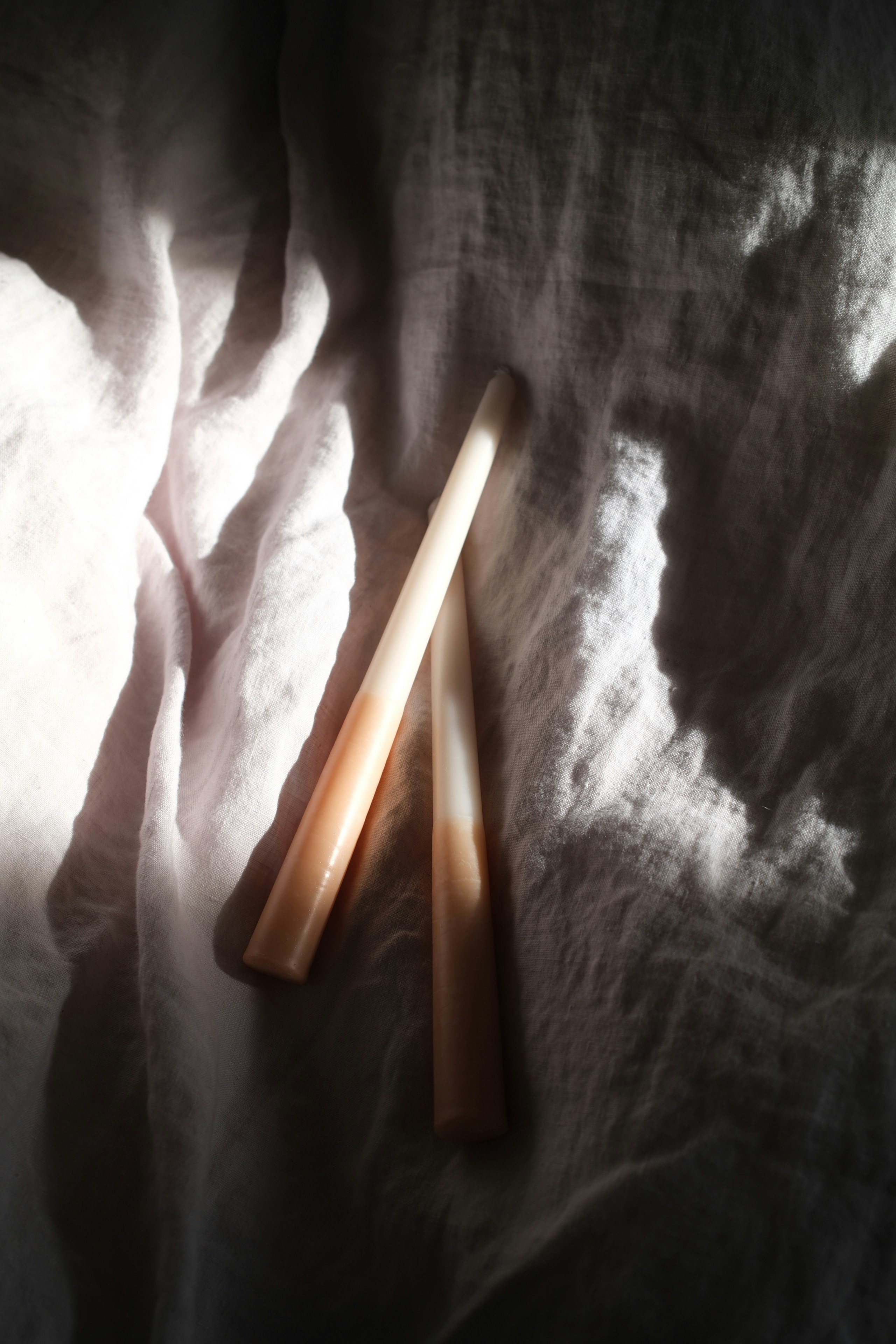 Two pale quartz rods resting on a wrinkled fabric under soft light