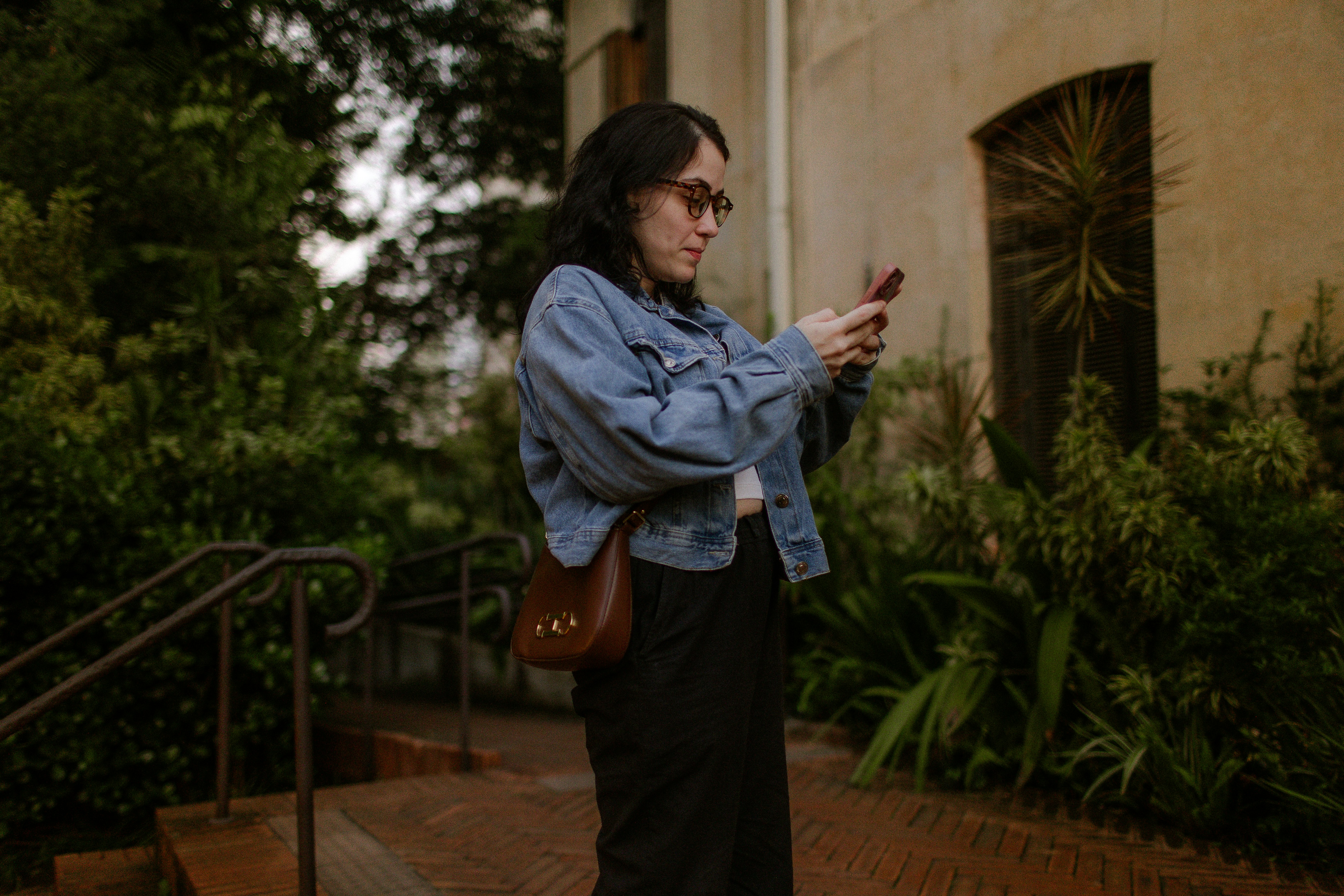 Portrait on the Steps: A Woman in Denim Focused on Her Phone