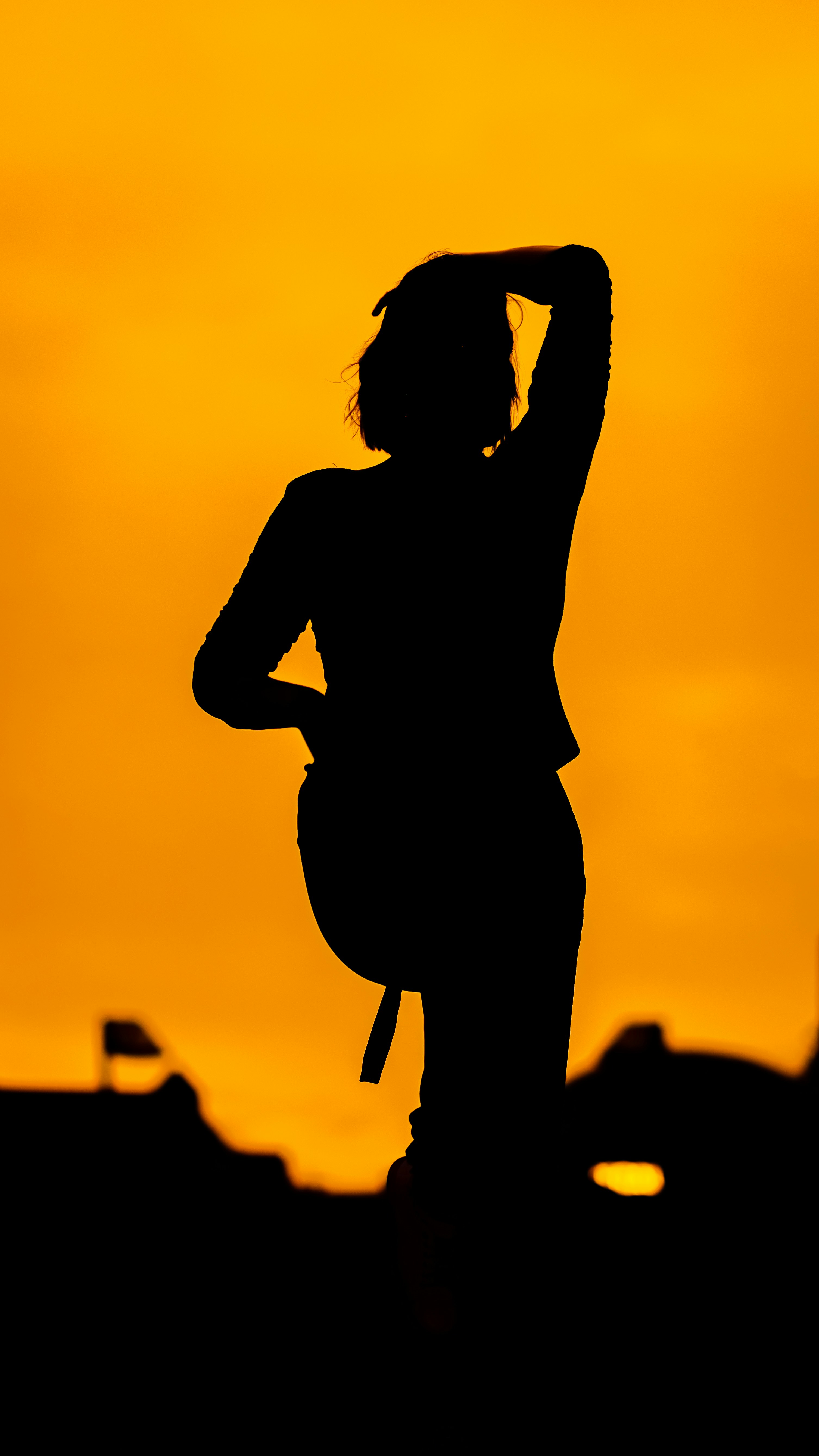Silhouette at Sunset: A Bold Stance Against a Tangerine Sky