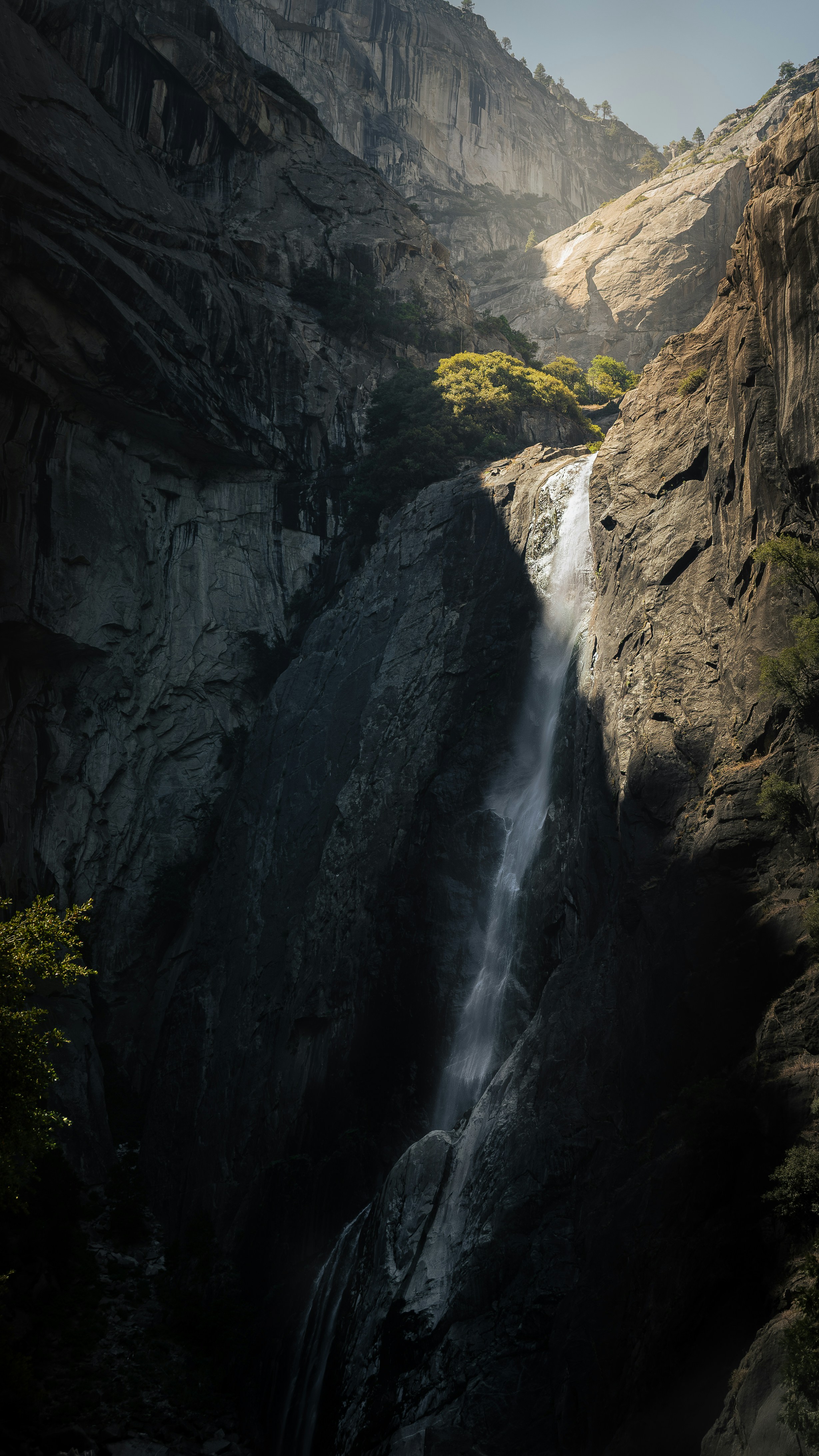 Cascading Light: A Canyon Waterfall Framed by High Cliff Faces