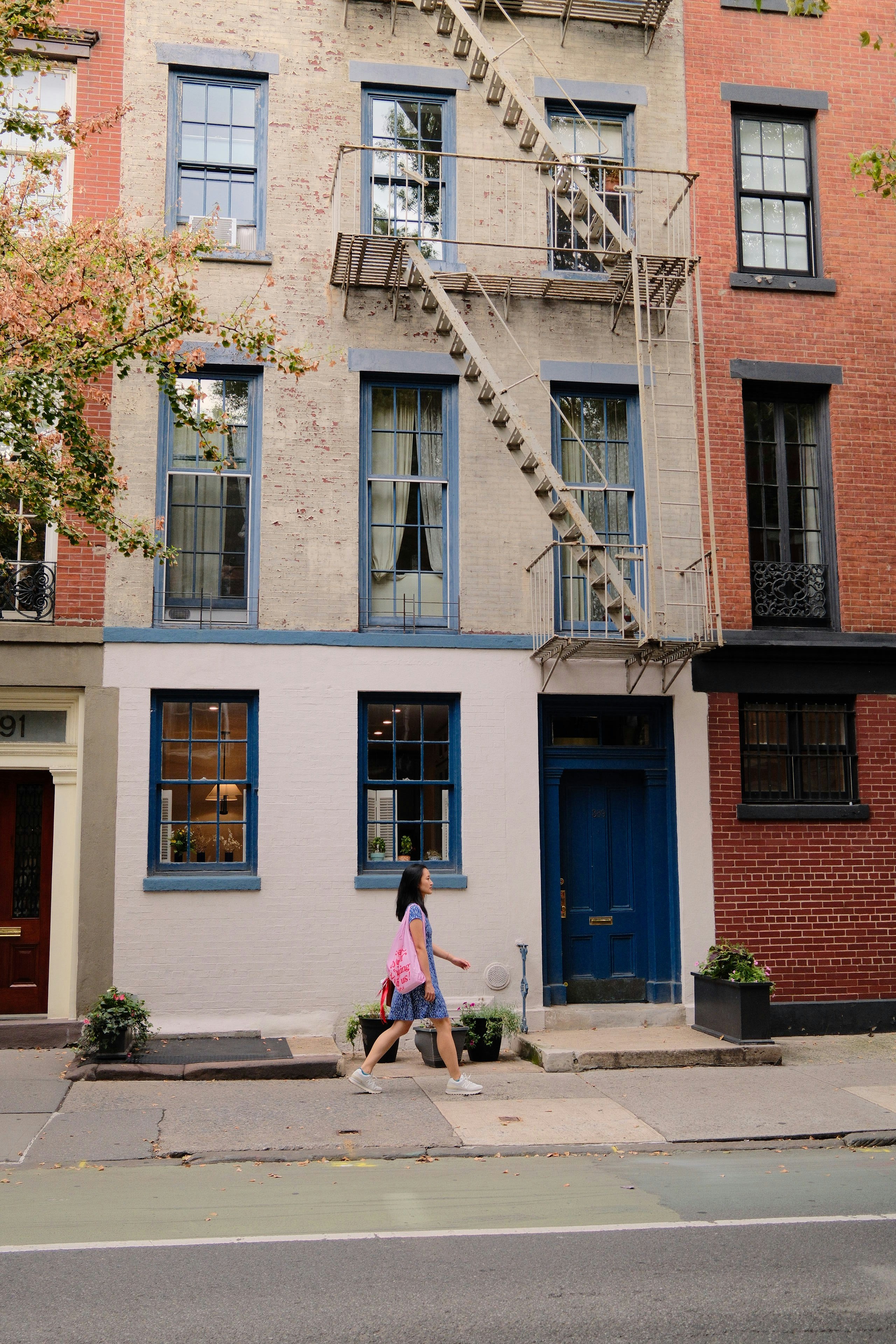 Pedestrian in a Quiet City Facade Walks Past a Colorful Row of Townhouse Windows