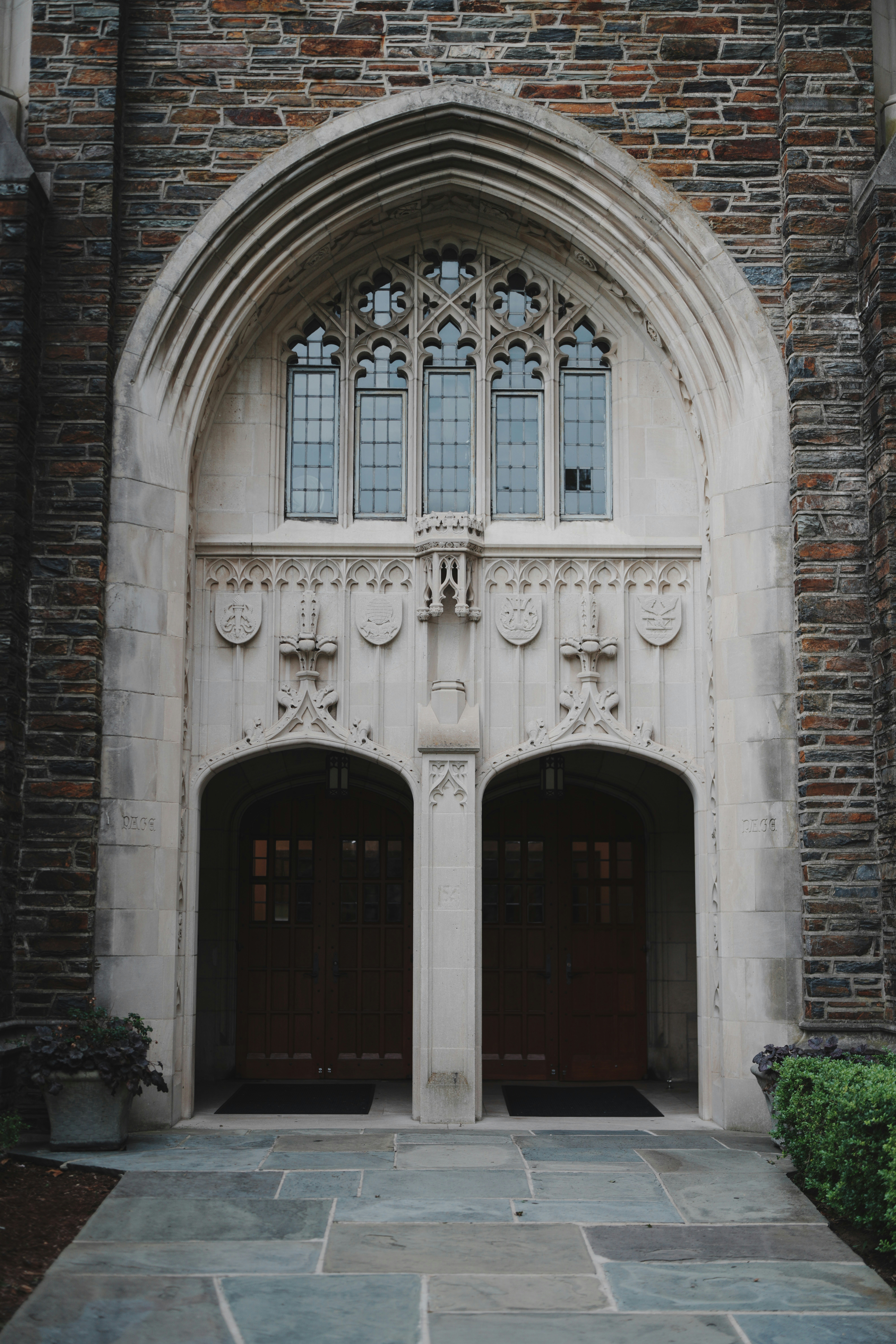 Gothic stone archway with double wooden doors and a leaded glass window above