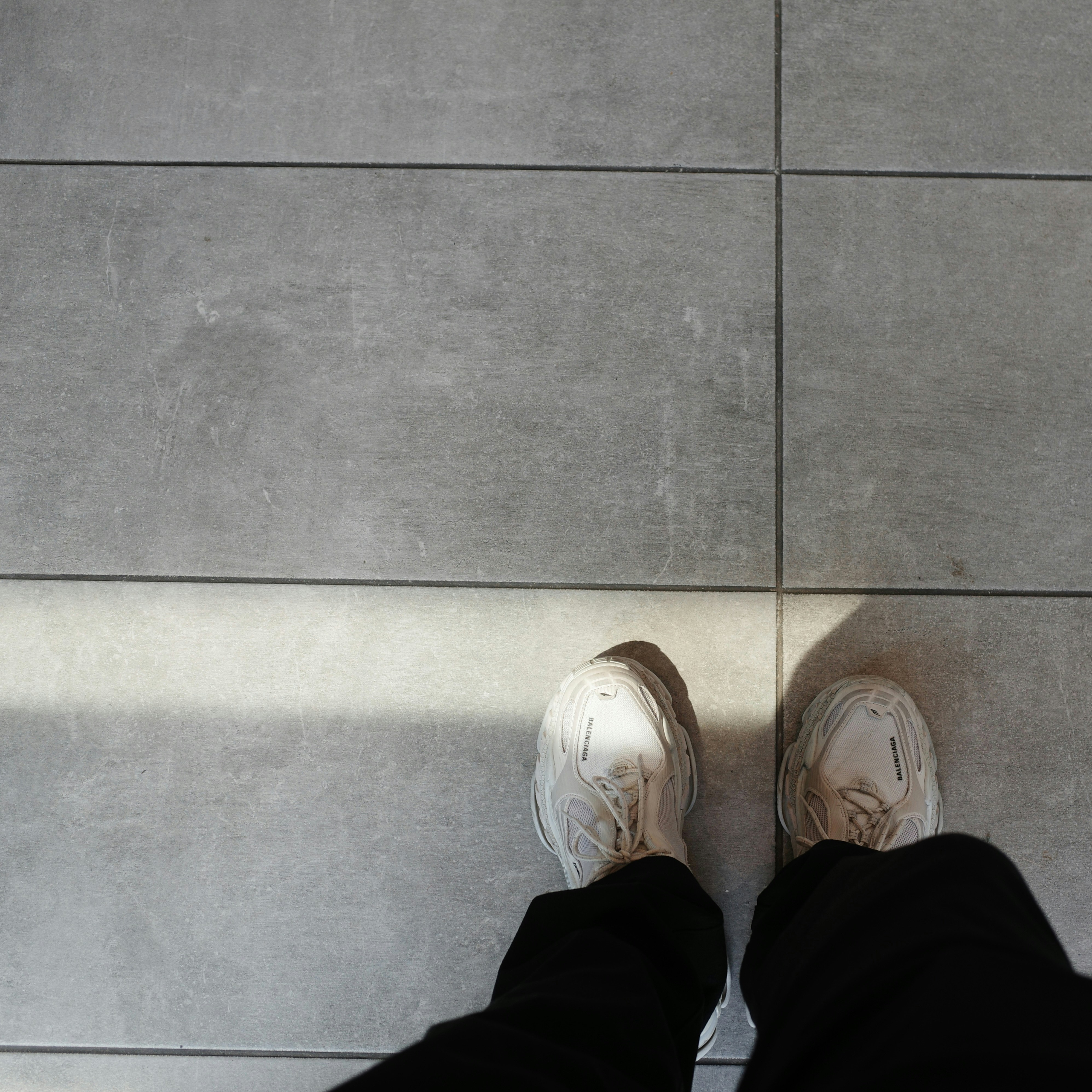 Step into the Grid: White Sneakers on Concrete Tiles