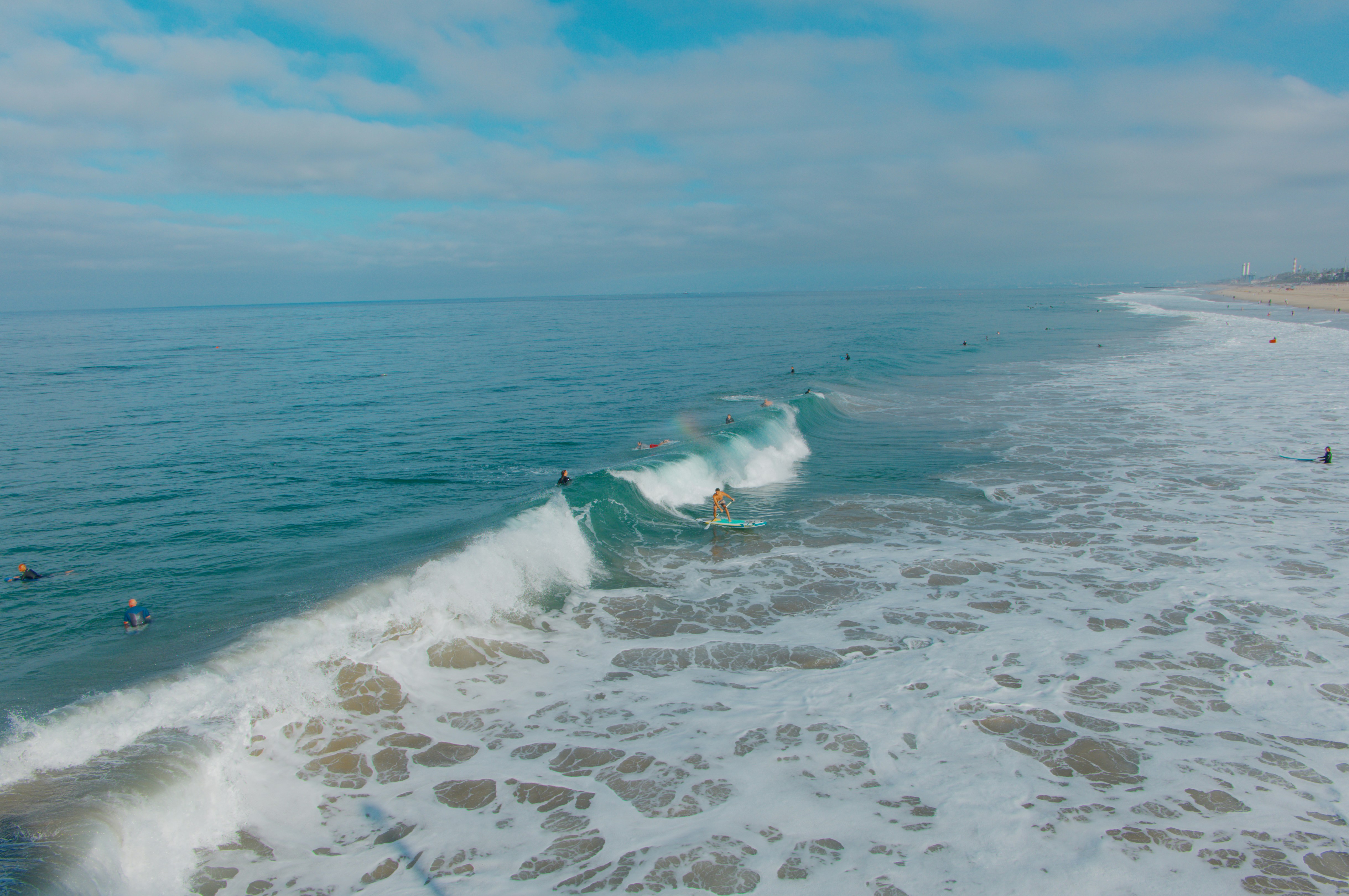 Surfer on a Cresting Wave Near a Quiet Coastal Strip