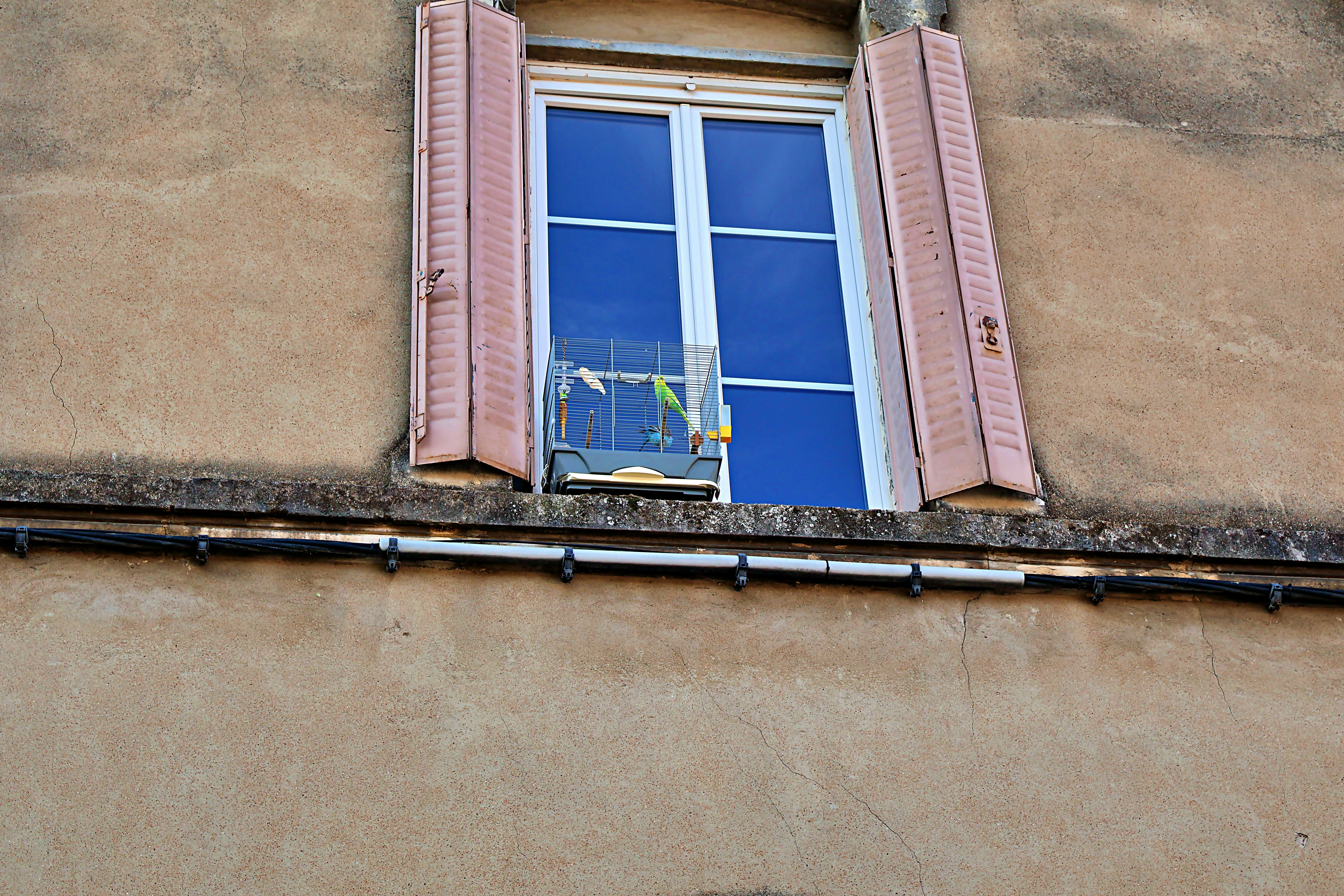 Blue Window with Pink Shutters: A Quiet Street Facade