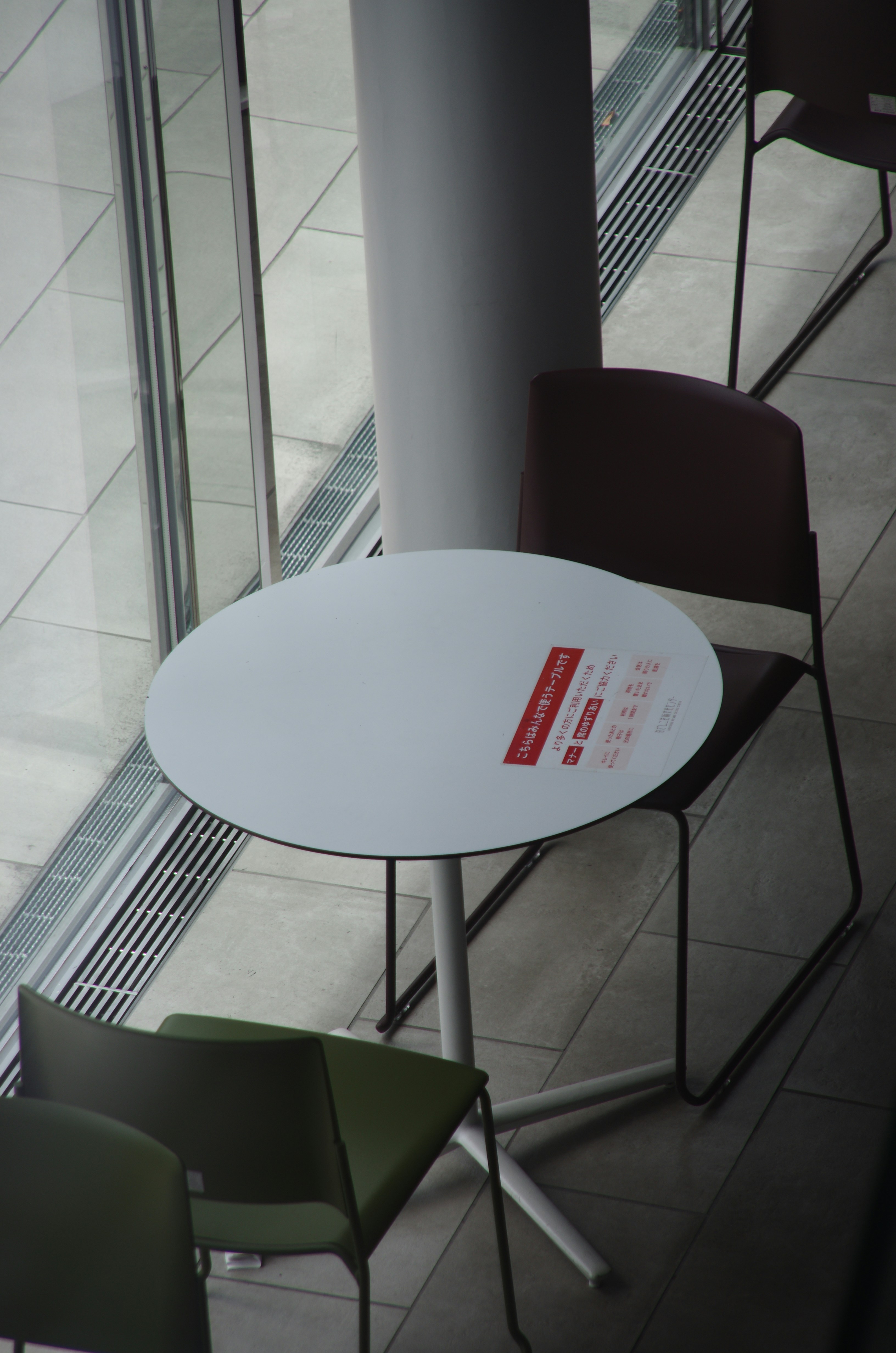 Minimalist Café Round: A White Table and Colored Chairs by the Window