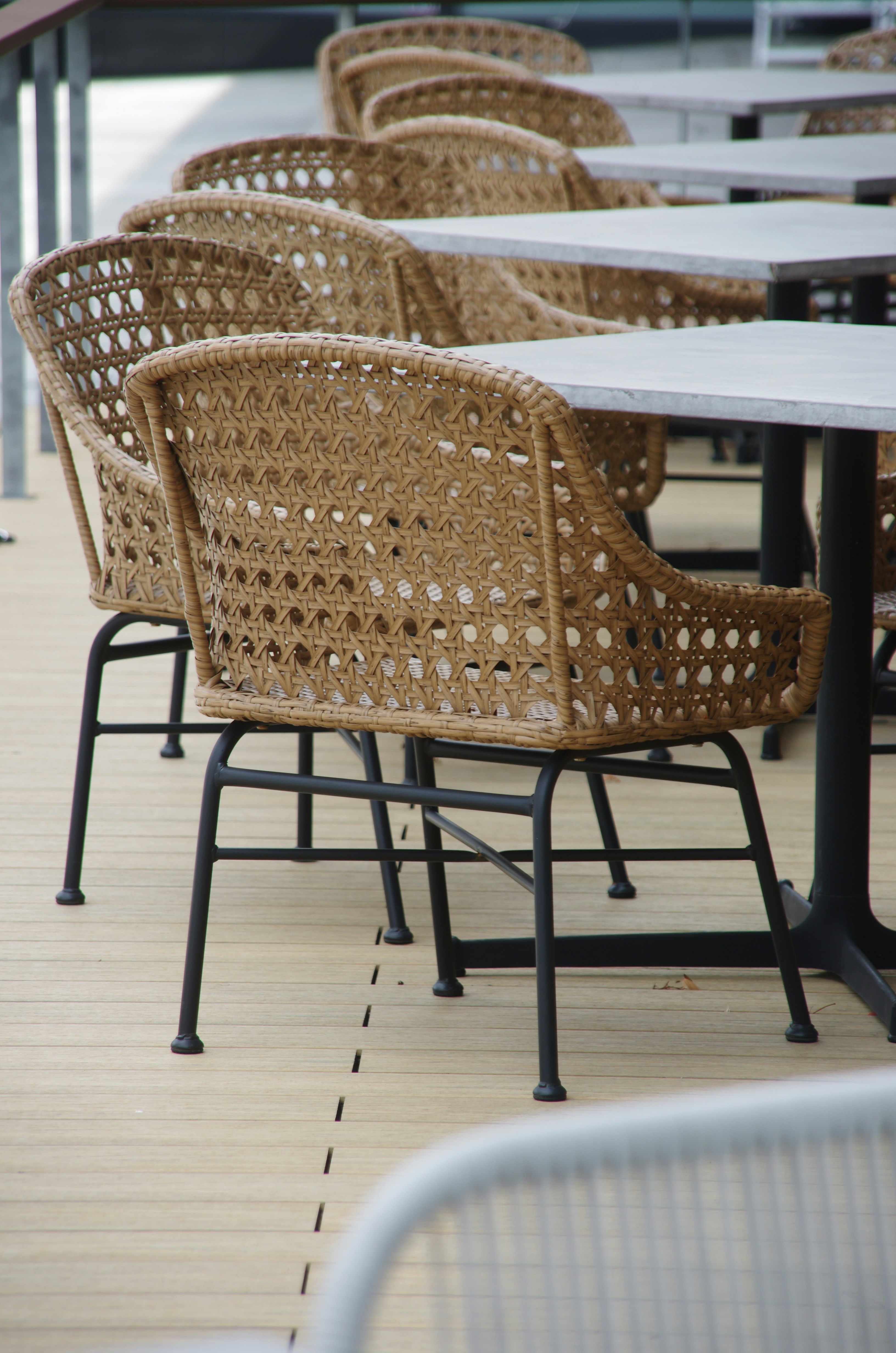 Row of woven cafe chairs along a sunlit deck