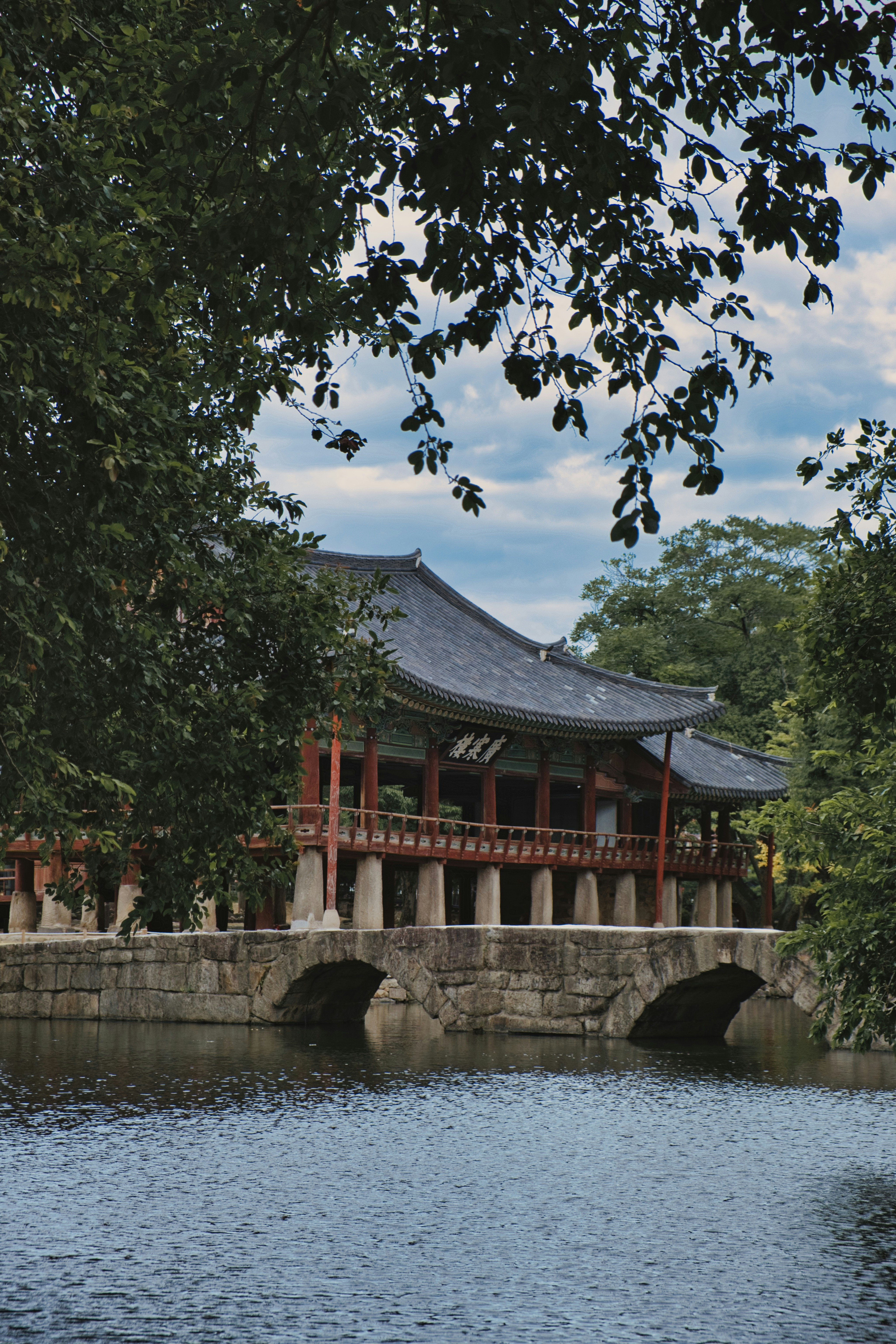 Stone Bridge Over Tranquil Water Framing a Traditional Pavilion