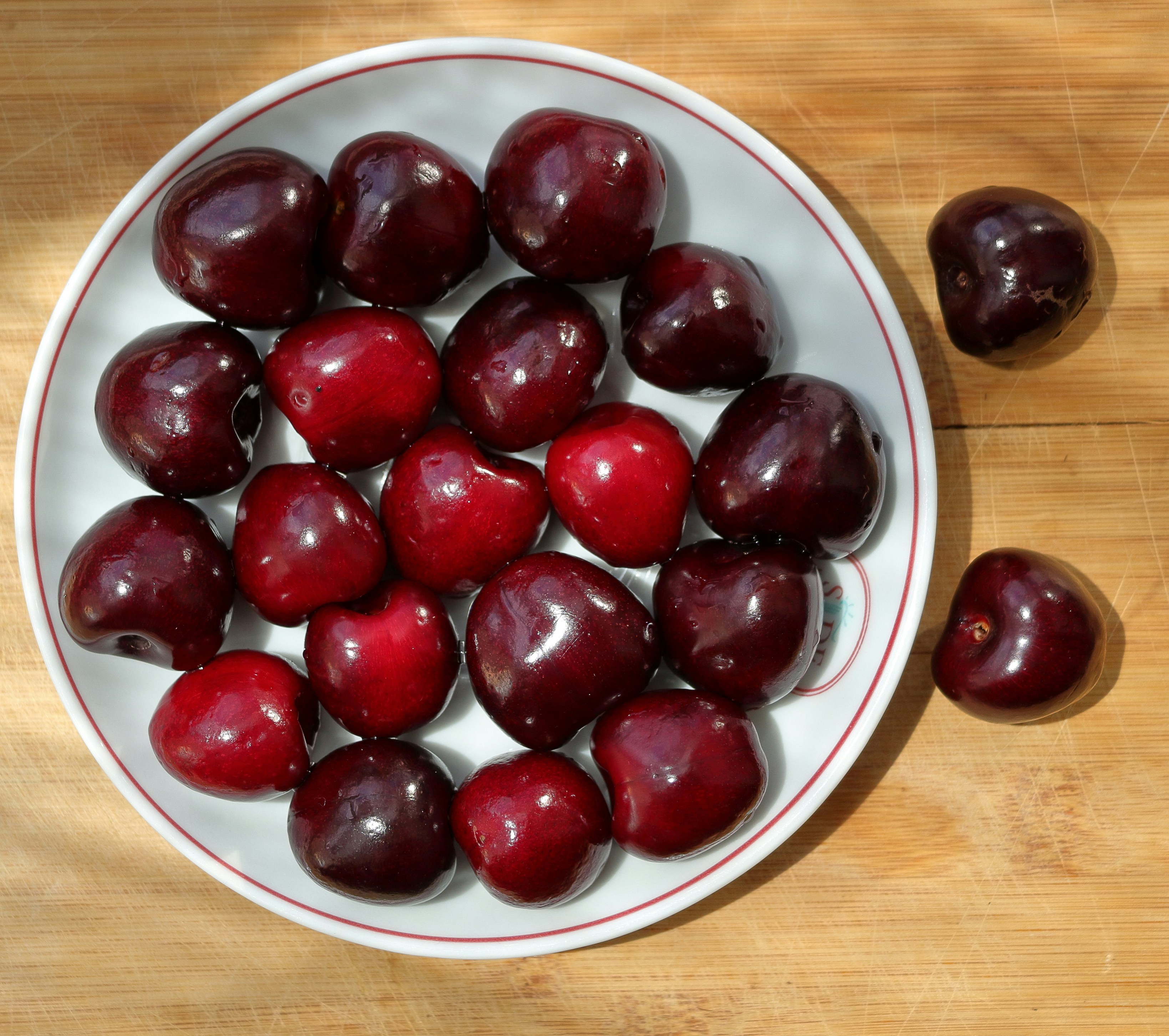 Scarlet Orchard: A Bowl of Glossy Cherries with Two Spillover Spheres