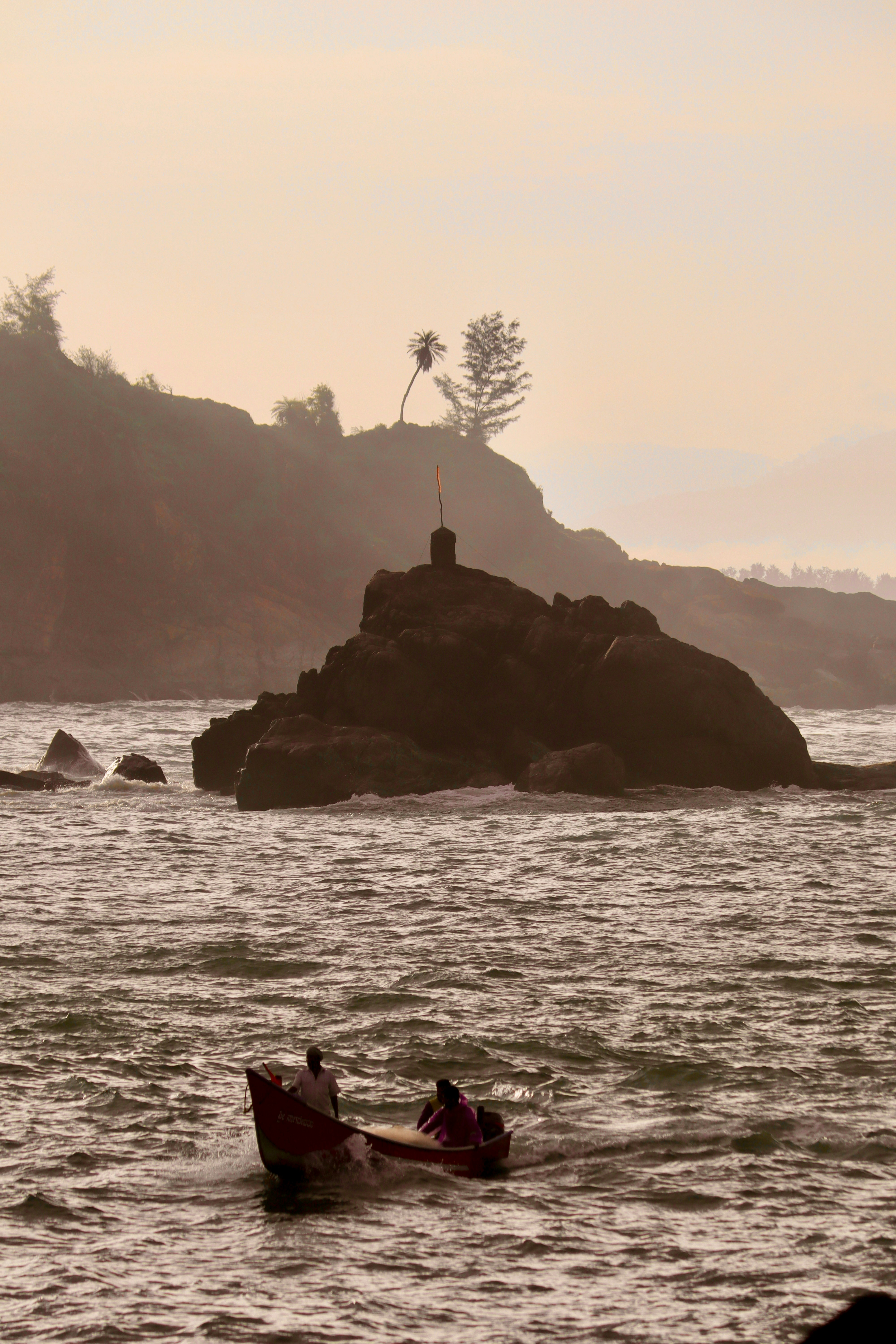 Distant Cove and Palm-Bound Rock: Sunset stillness over a lone rowboat