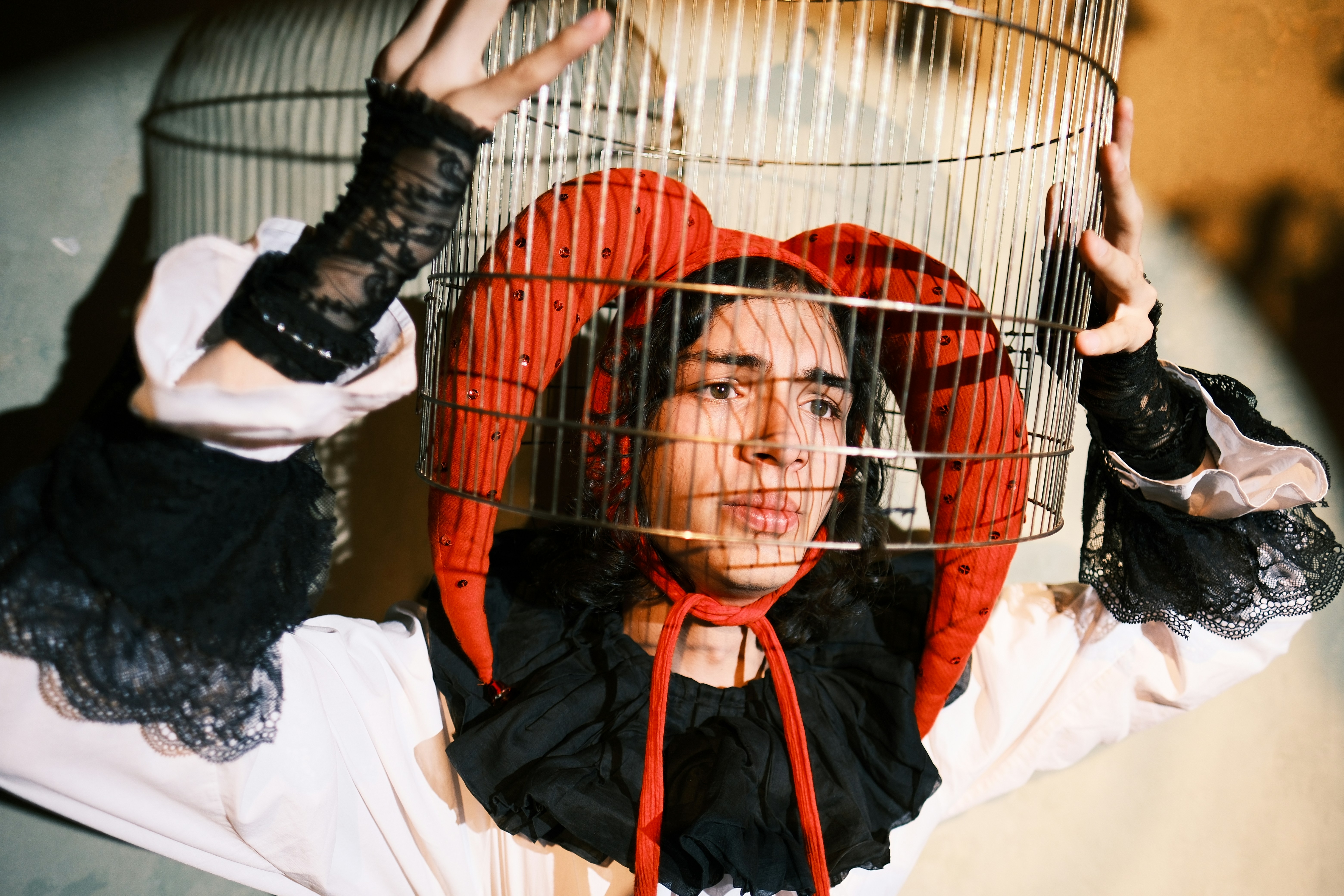 Caged Identity: A Youthful Performer Under a Red Hat and Veiled Confession