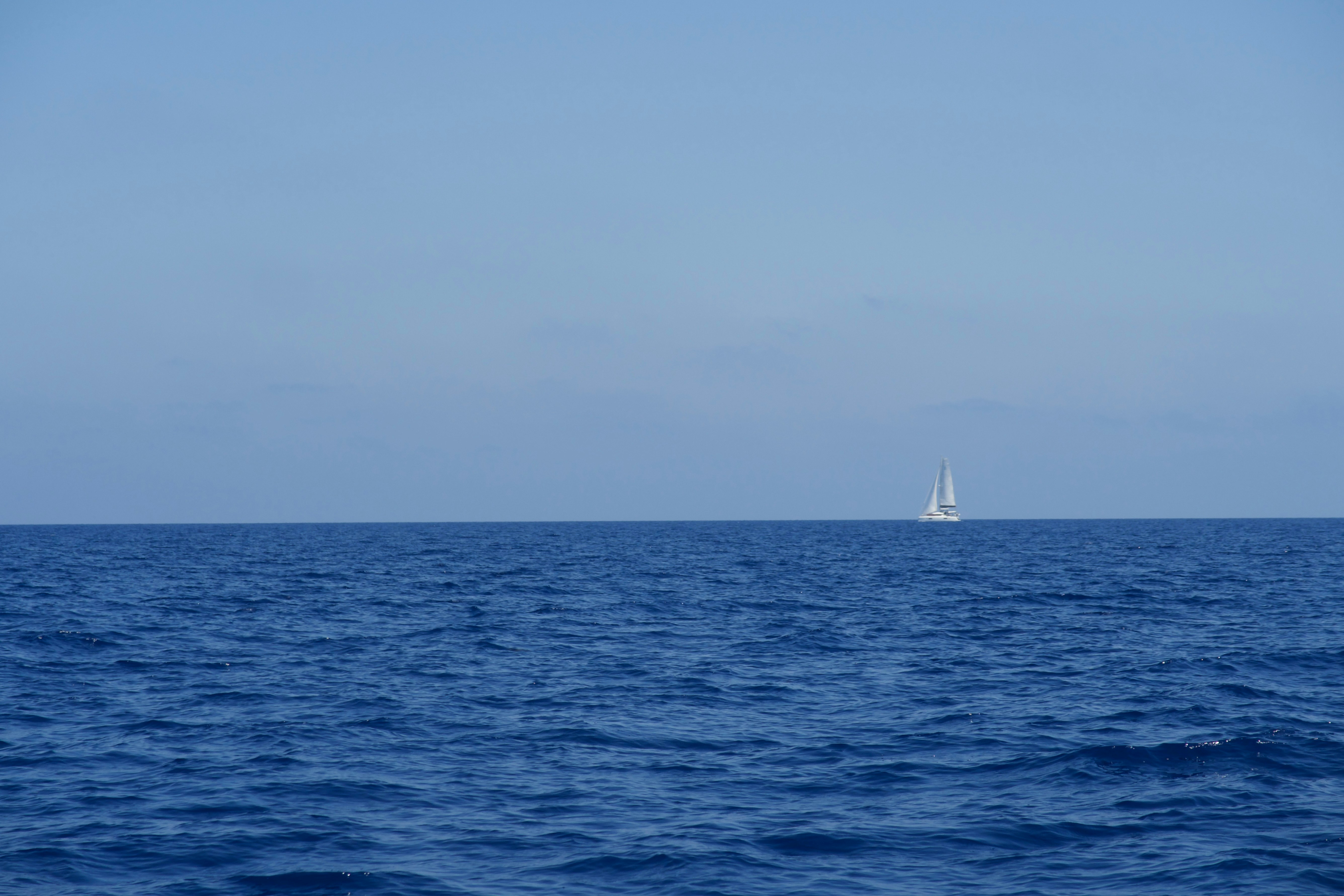 Sail on the Horizon: A Distant Boat Across Open Sea