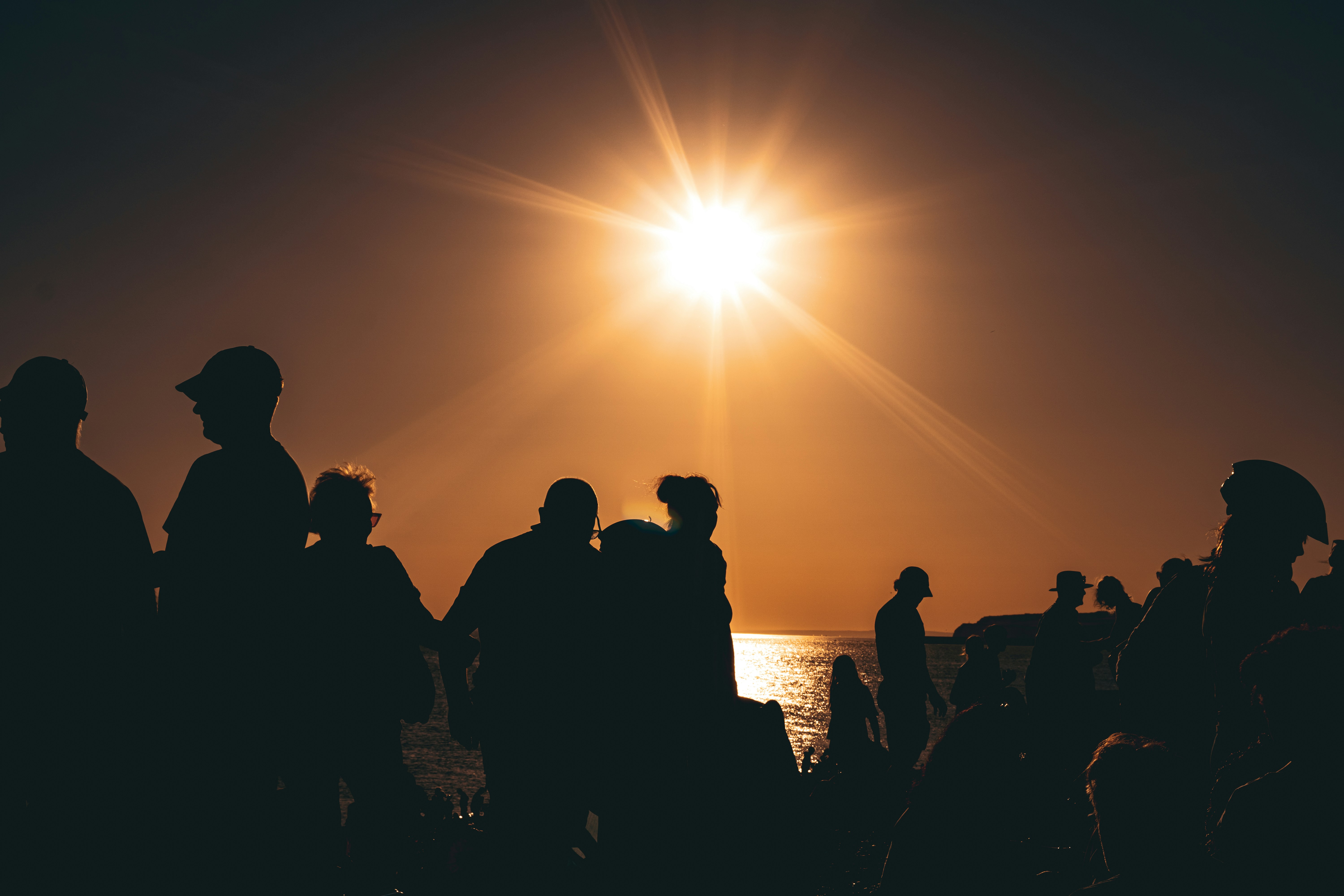 Sunset Silhouettes: A Crowd at Dusk by the Shore