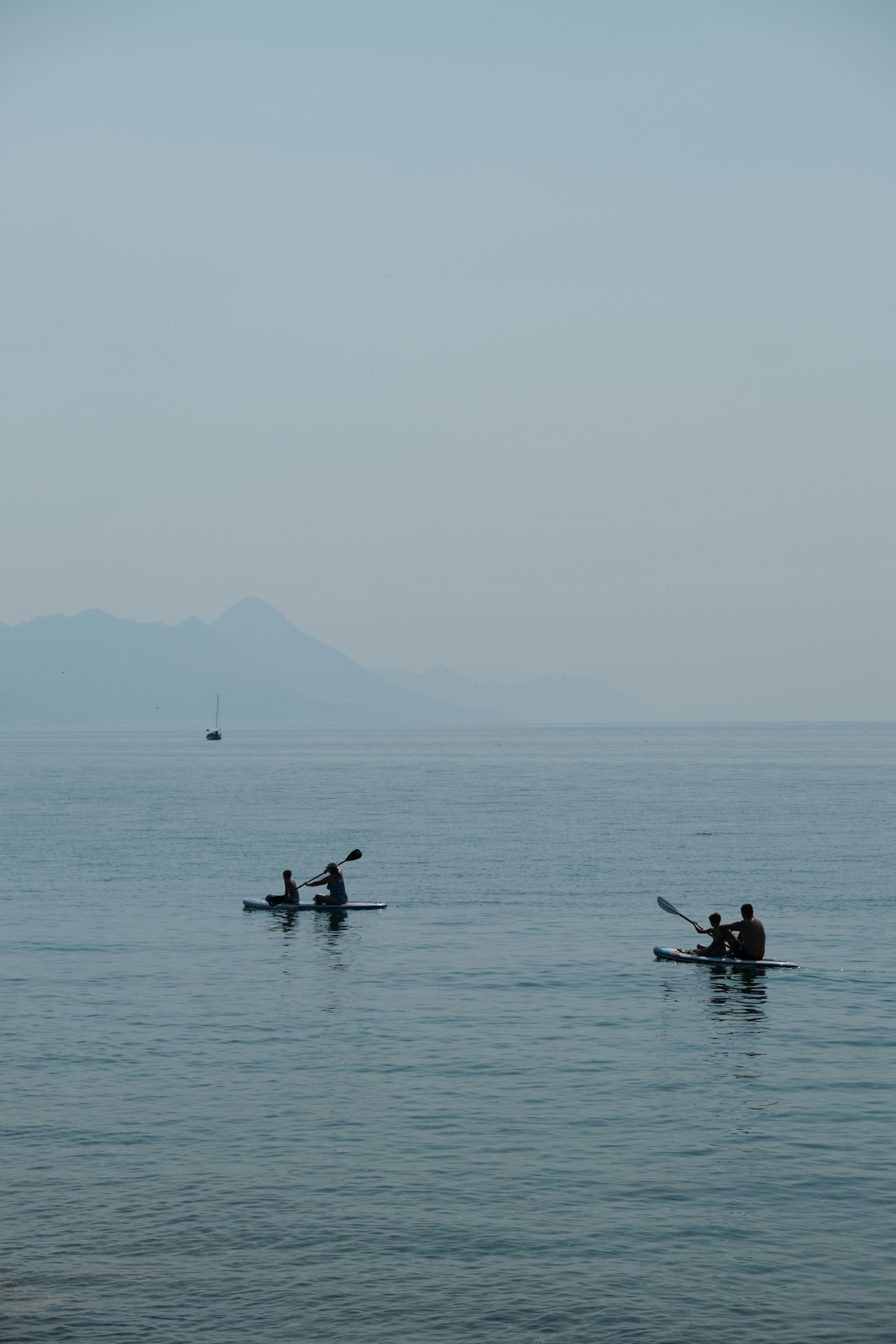 Silent Canoe: silhouettes on a calm sea under a pale horizon