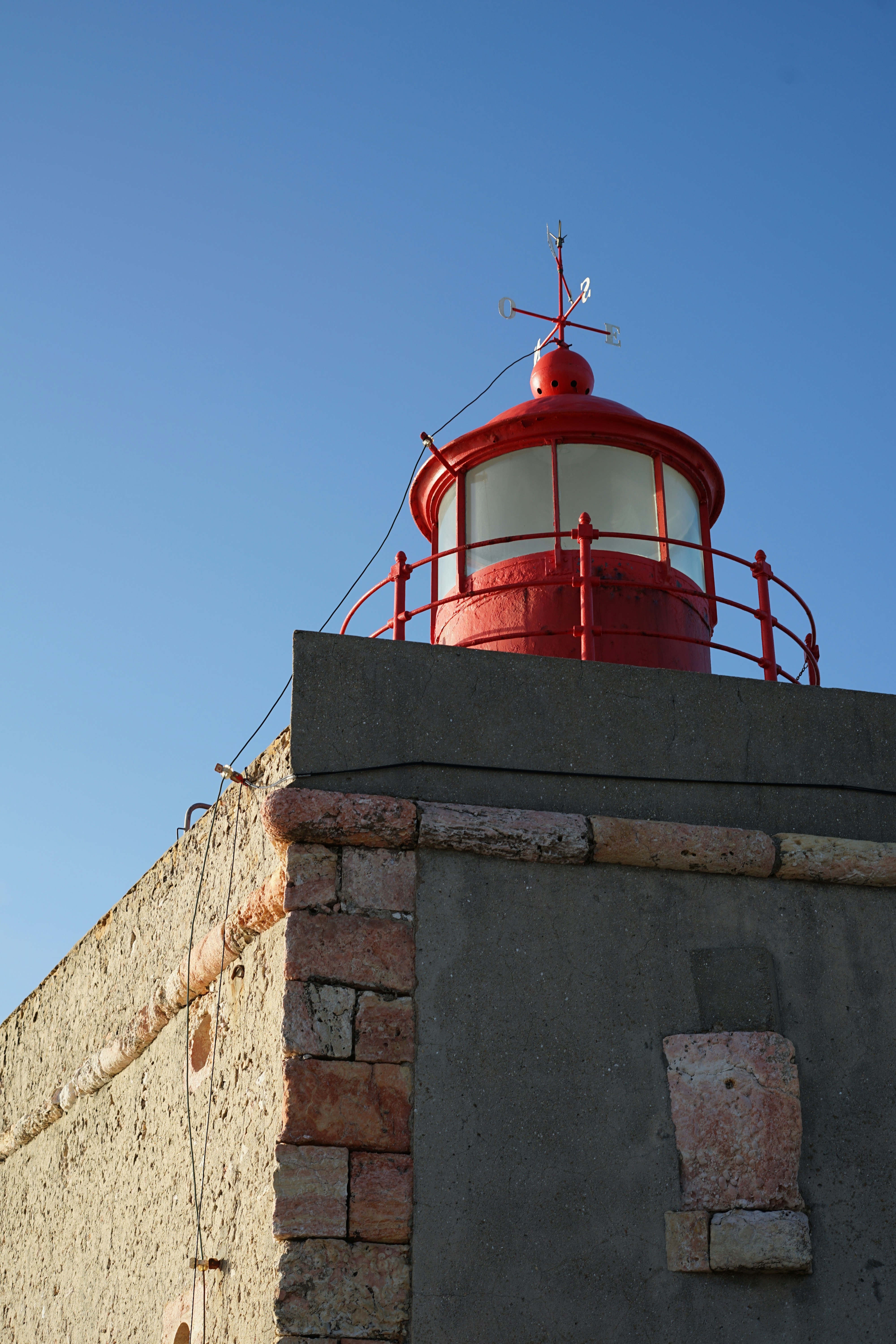Red Beacon at Dusk: A Lighthouse Crowned on a Concrete Rampart