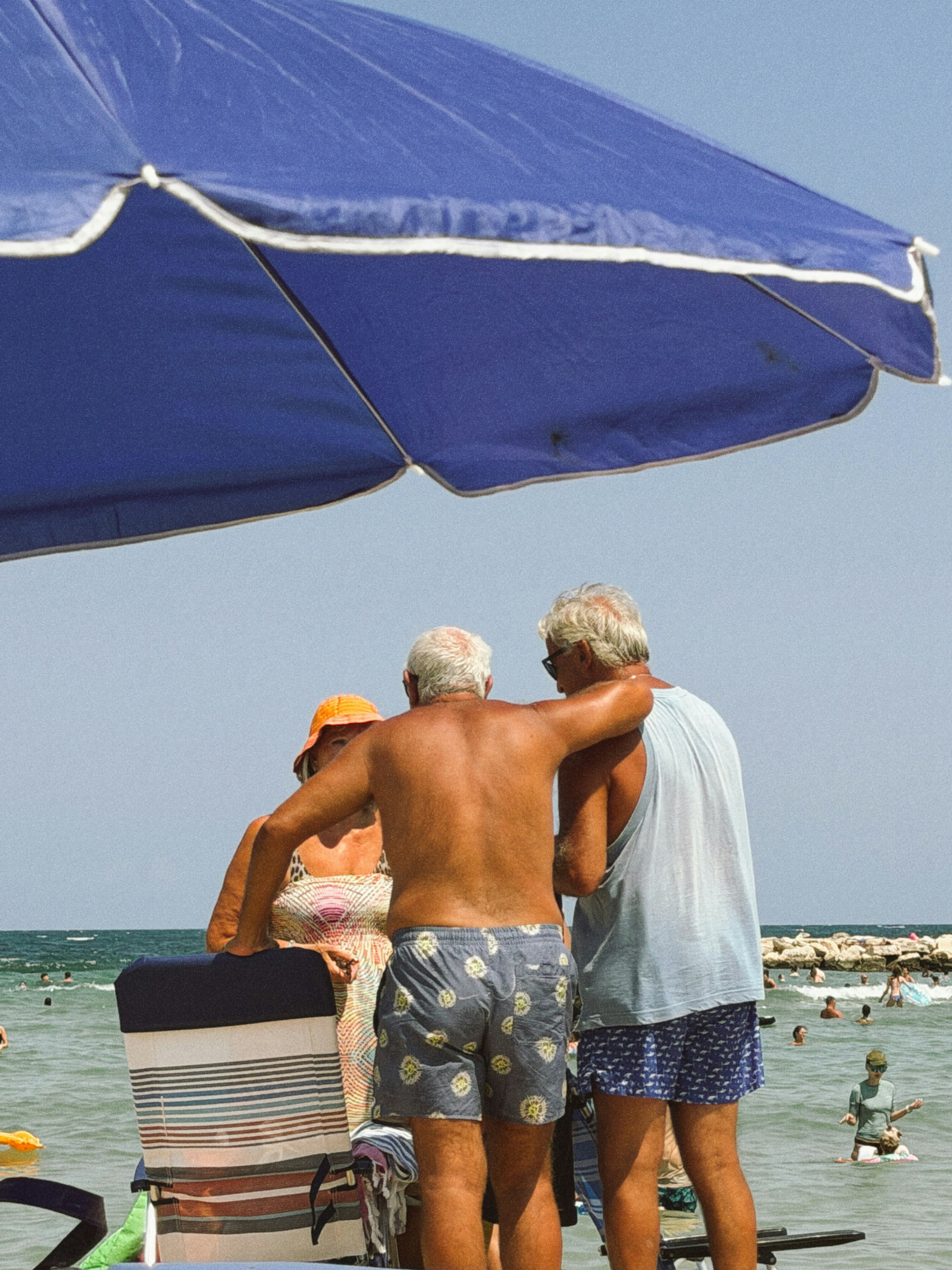 Sunlit Beach Portrait: Three Friends Under a Blue Umbrella