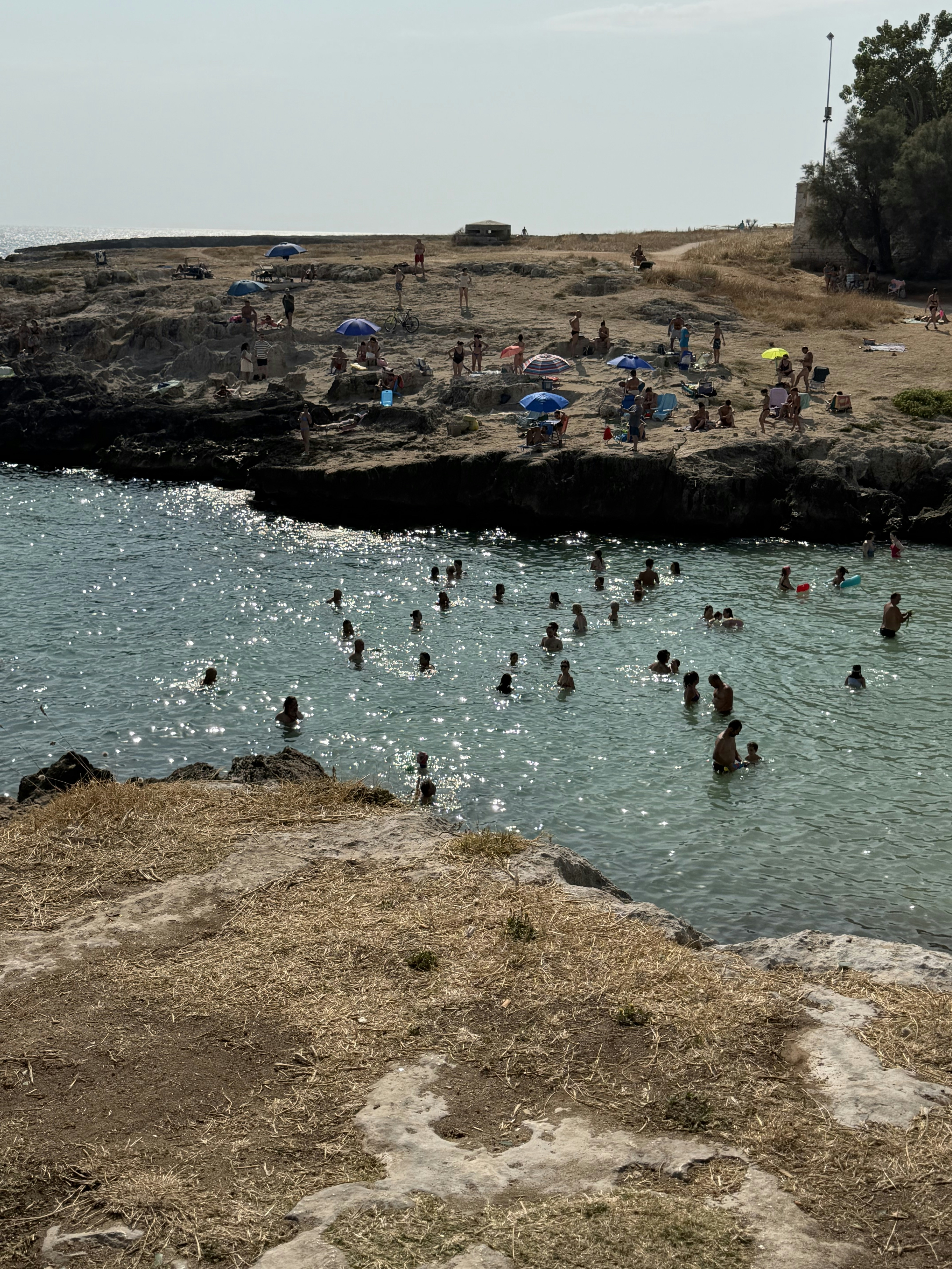 Sunlit Cove: A Busy Cala with Turquoise Waters and Umbrella Quilting