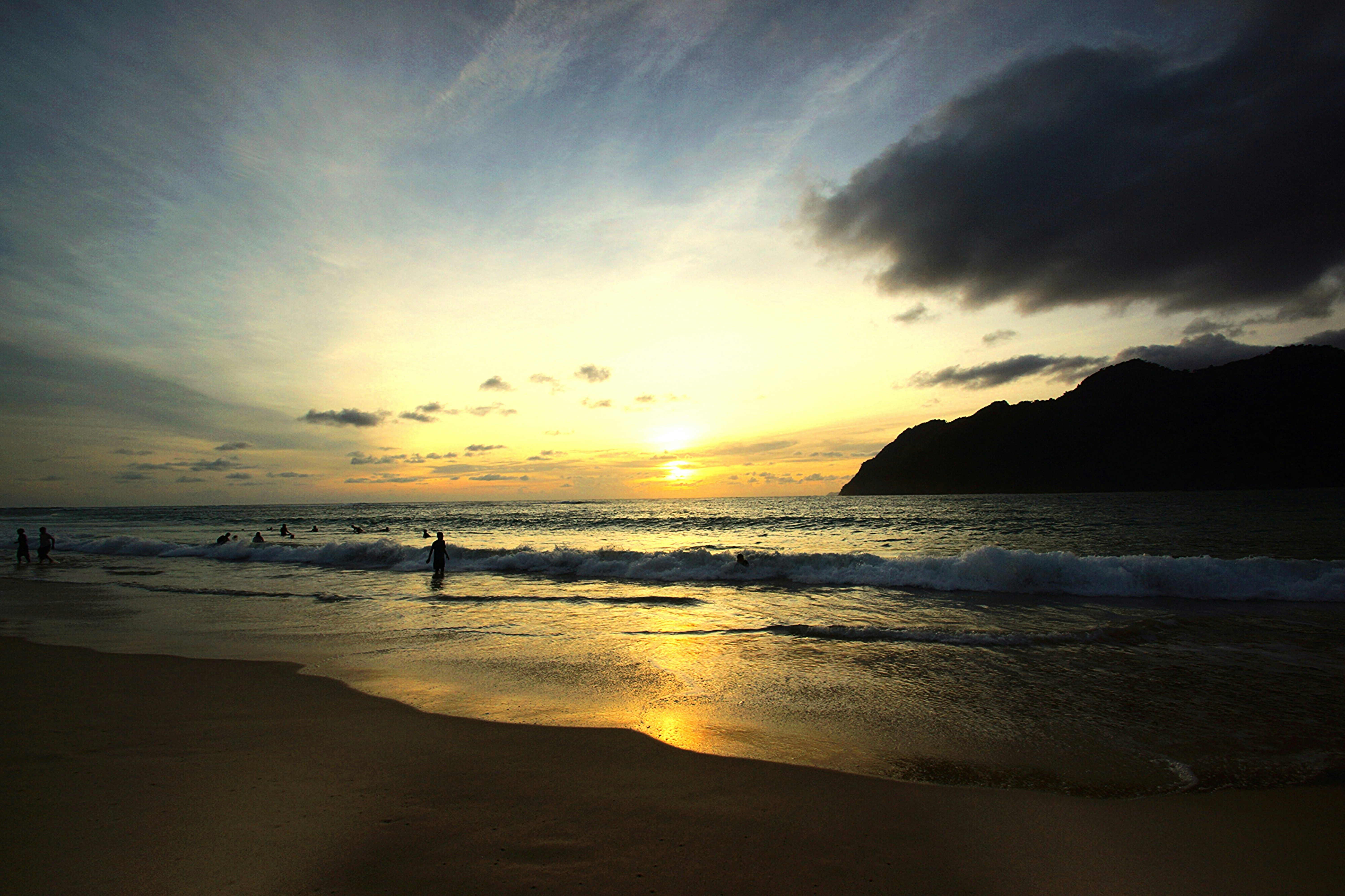 Sunlit Shoreline at Golden Hour with Distant Silhouettes