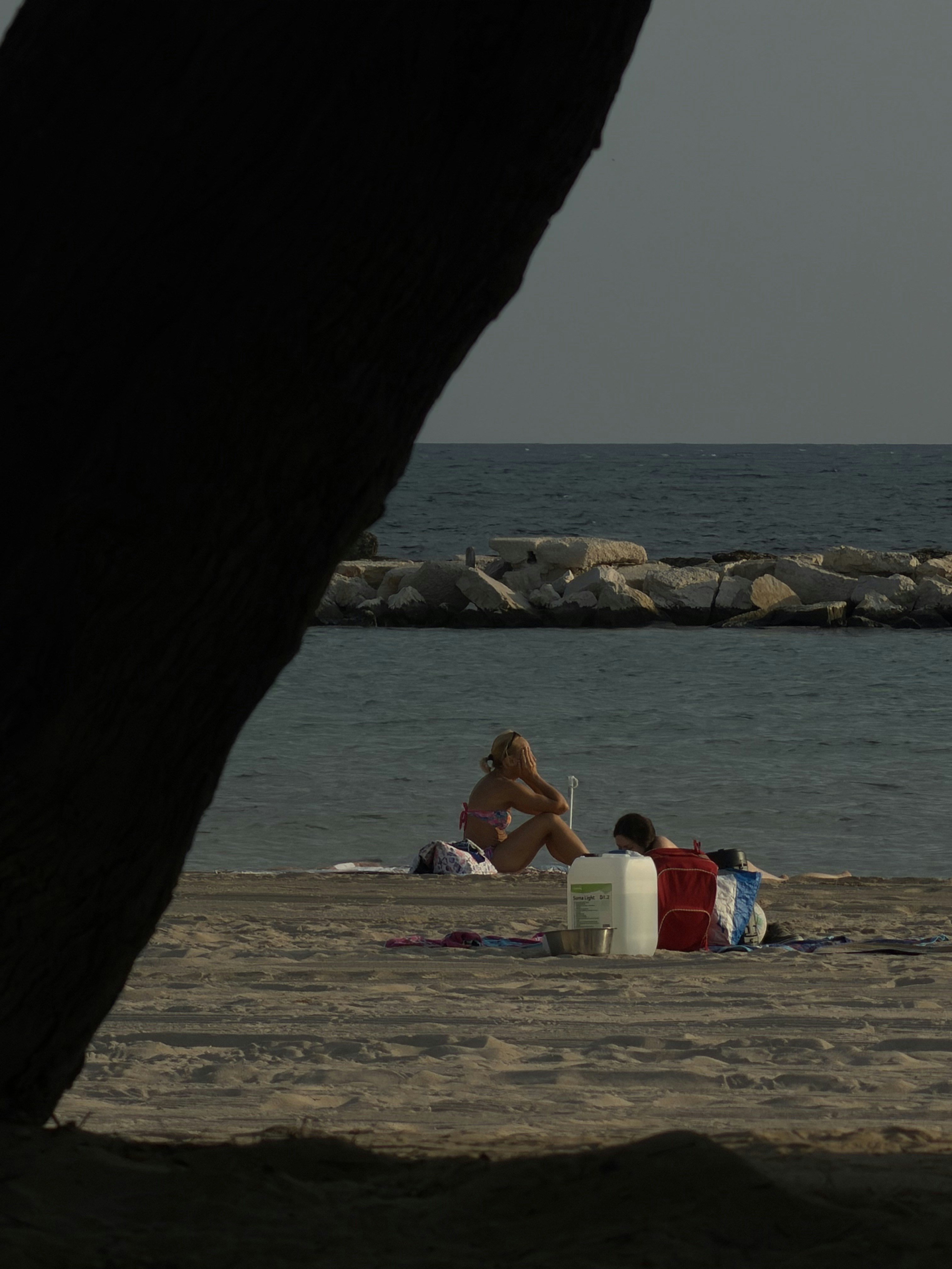 Shade and Seashells: Beachgoers Beneath a Dark Arch