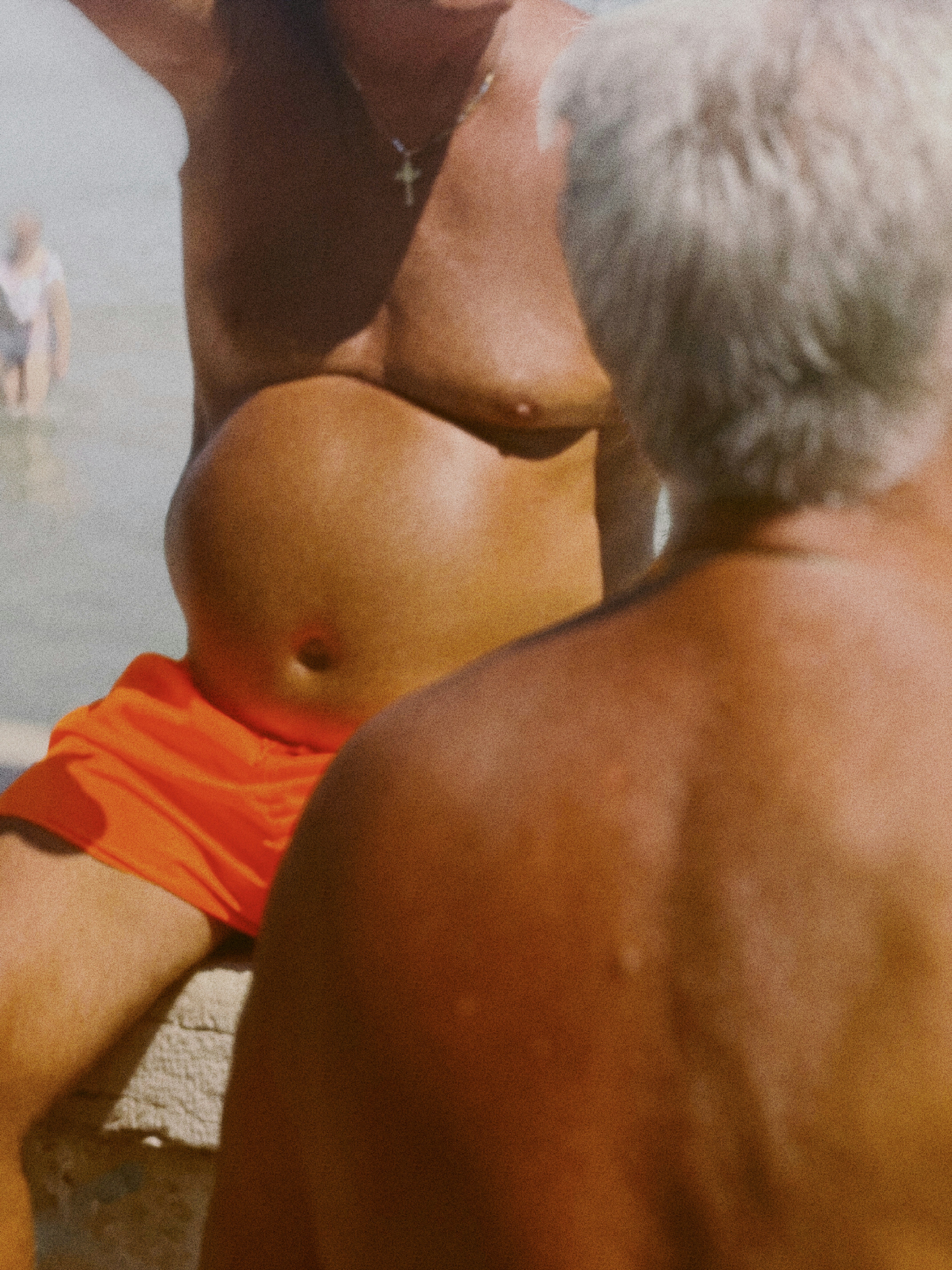 Sunlit beach moment: layered bodies by a brick barrier