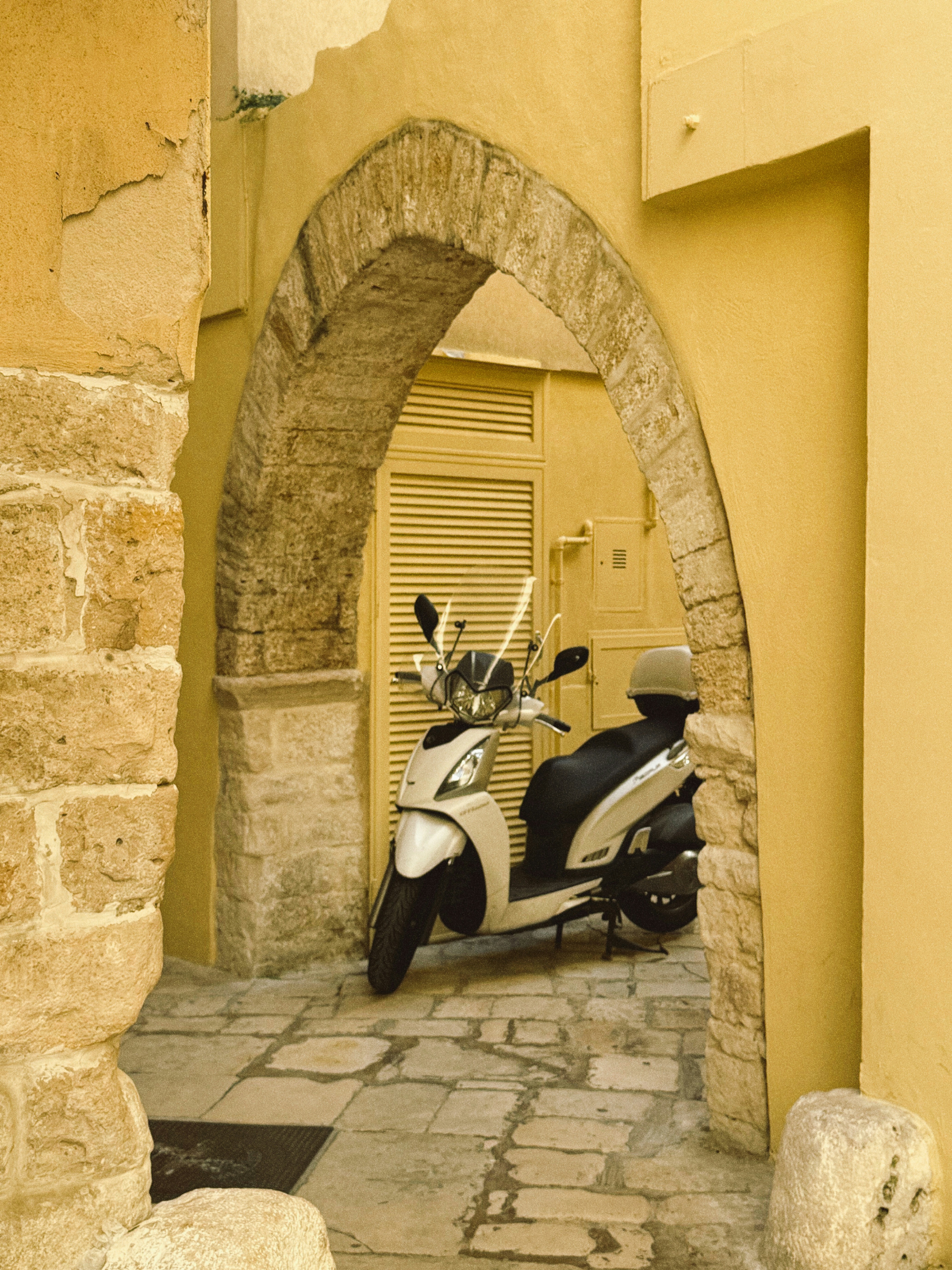 Scooter Quietly Guarded Under a Stone Arch