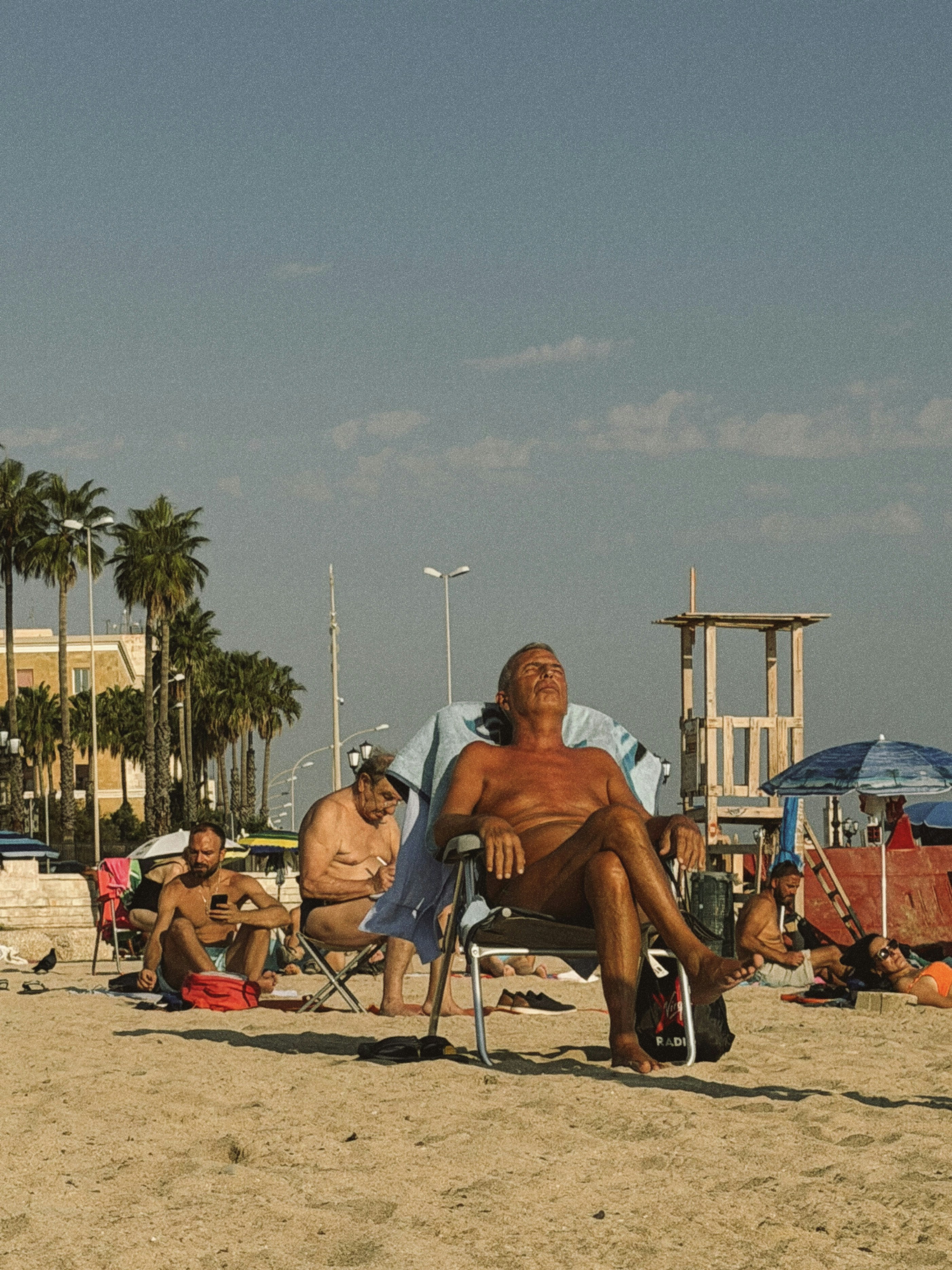 Sunbather on a crowded beach: a sunlit escape framed by palm trees