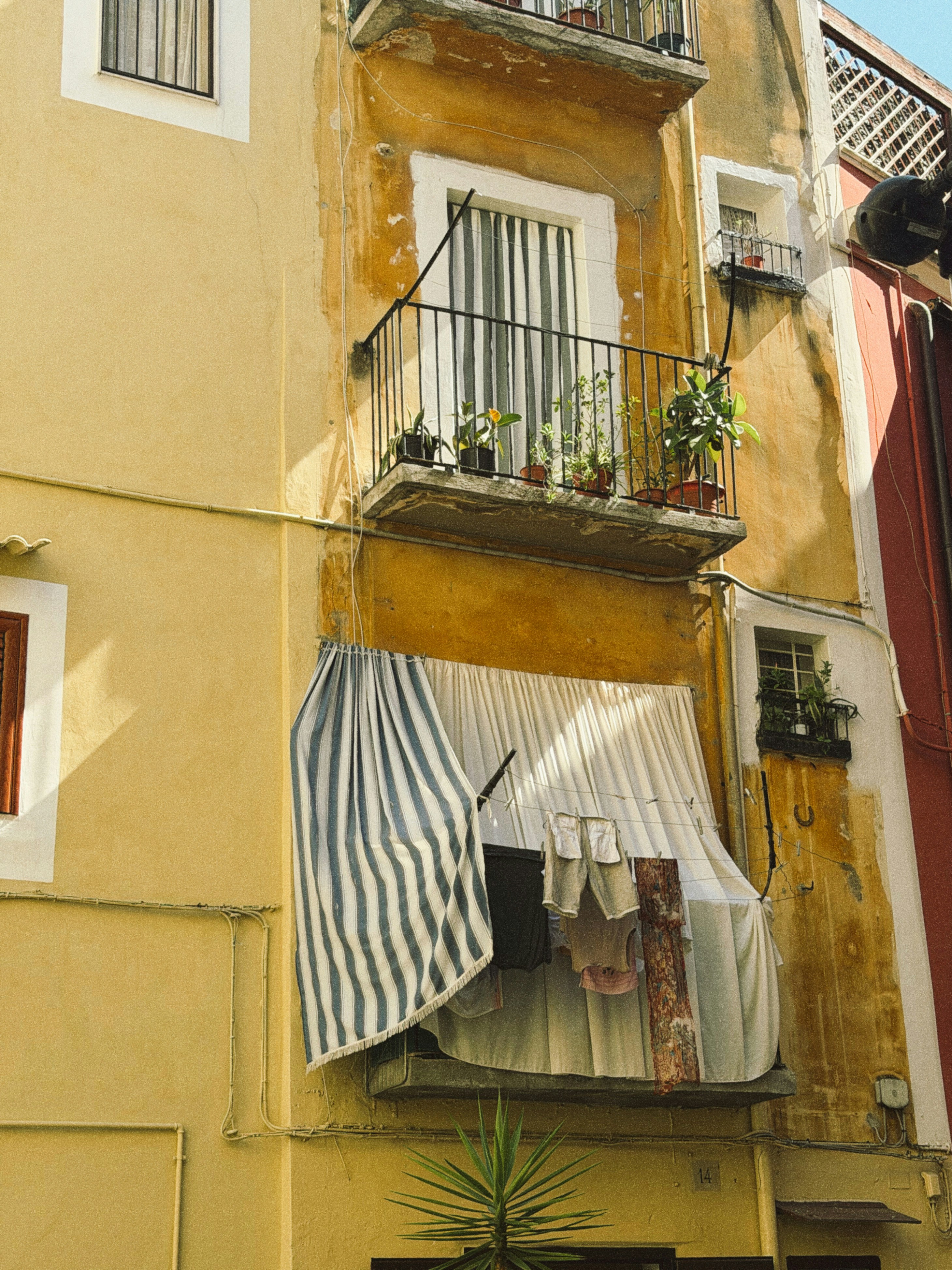 Yellow Facade with Balcony and Striped Canopy